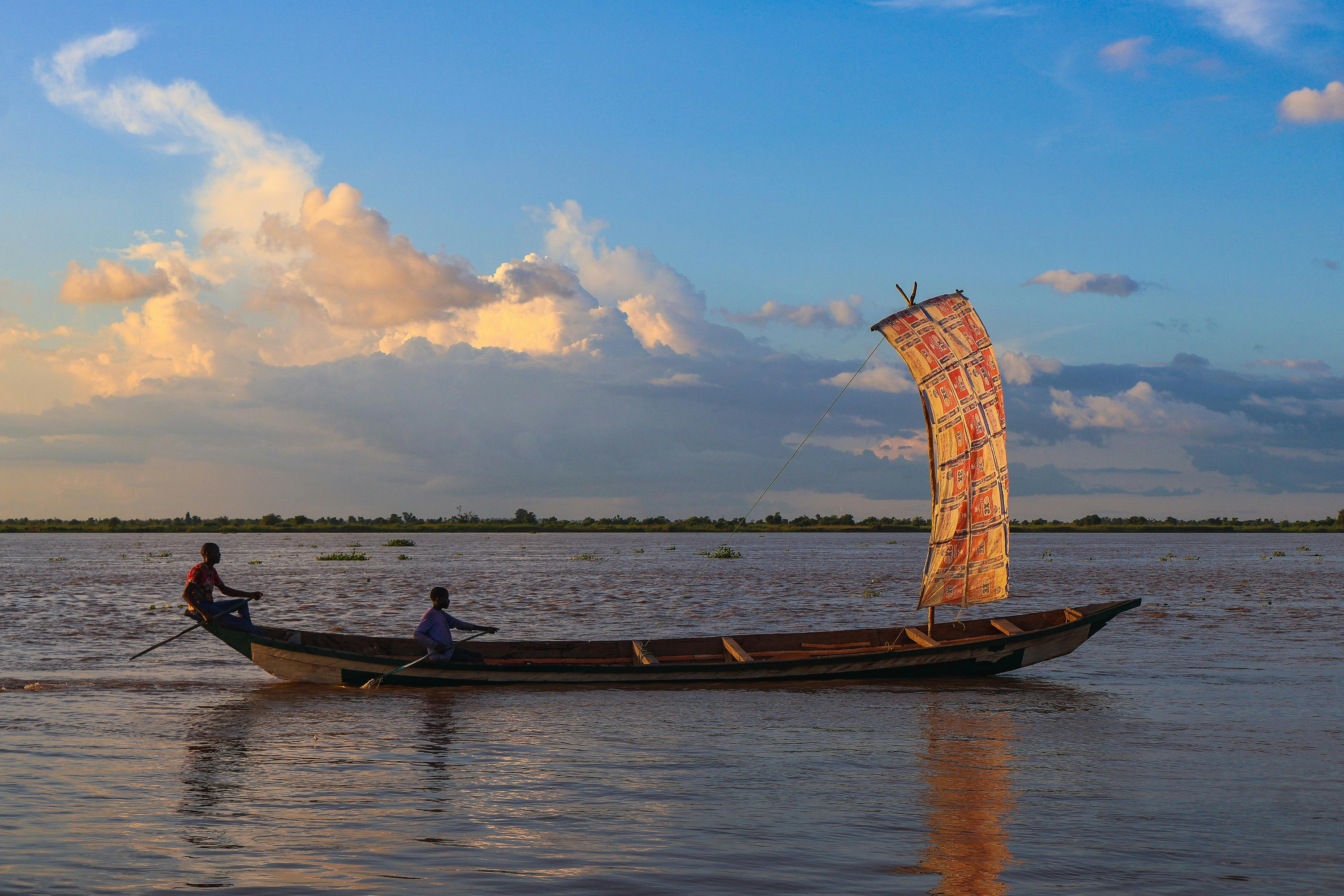 Traditional Canoe Sailing at Sunset on River · Free Stock Photo
