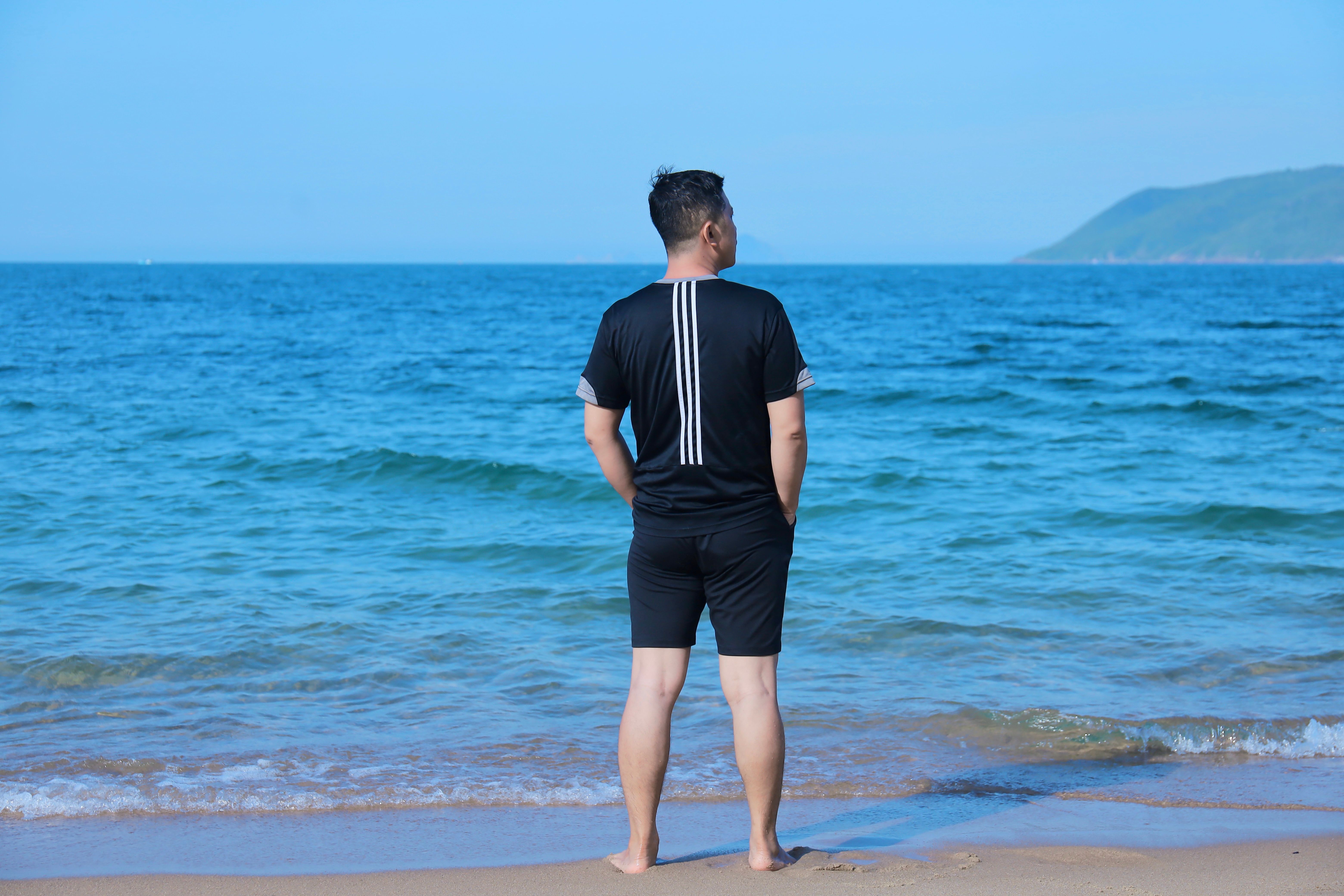 Man Standing on Beach Facing Ocean in Summer · Free Stock Photo
