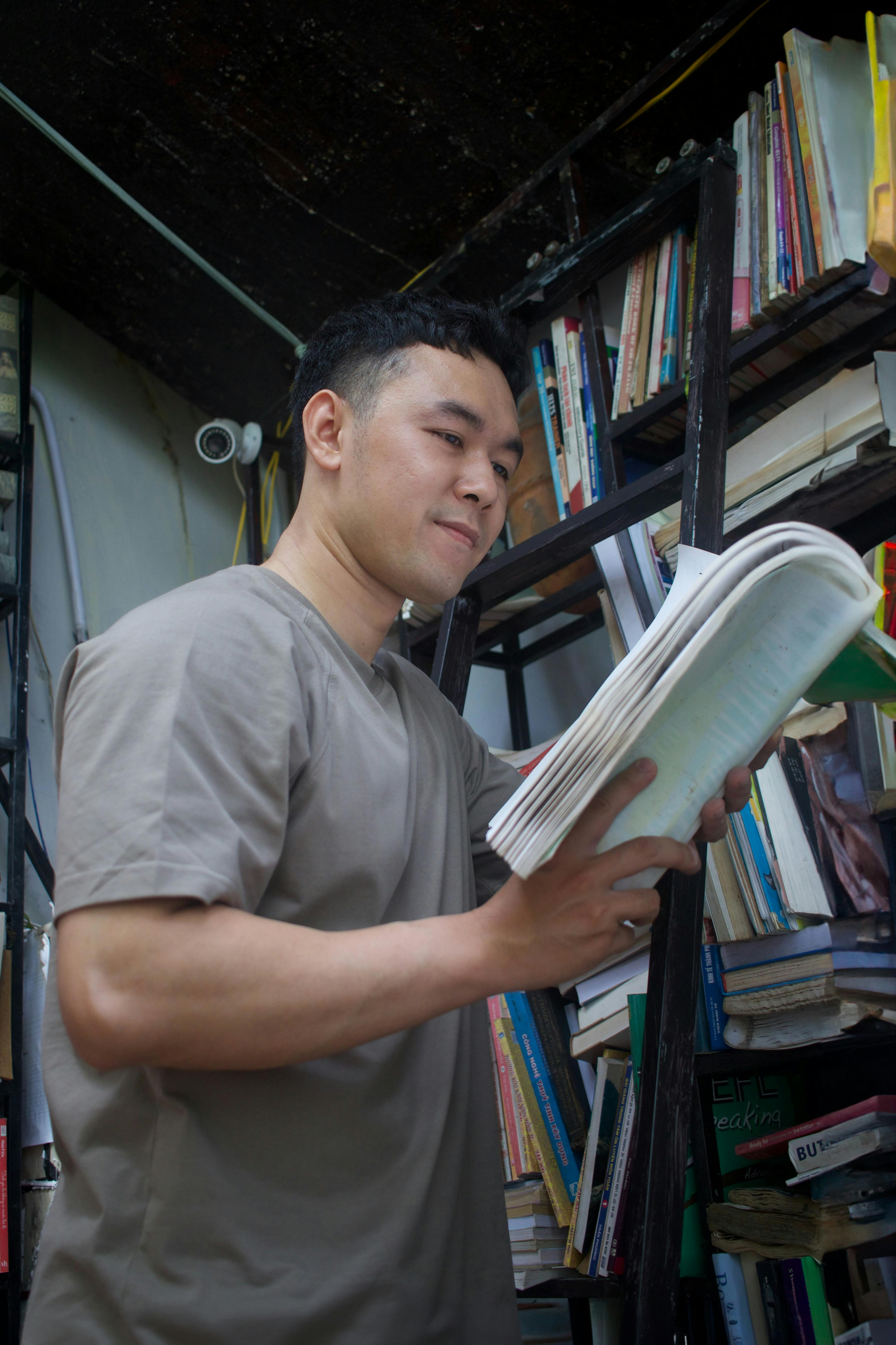 Man Reading in a Crowded Bookstore Aisle · Free Stock Photo