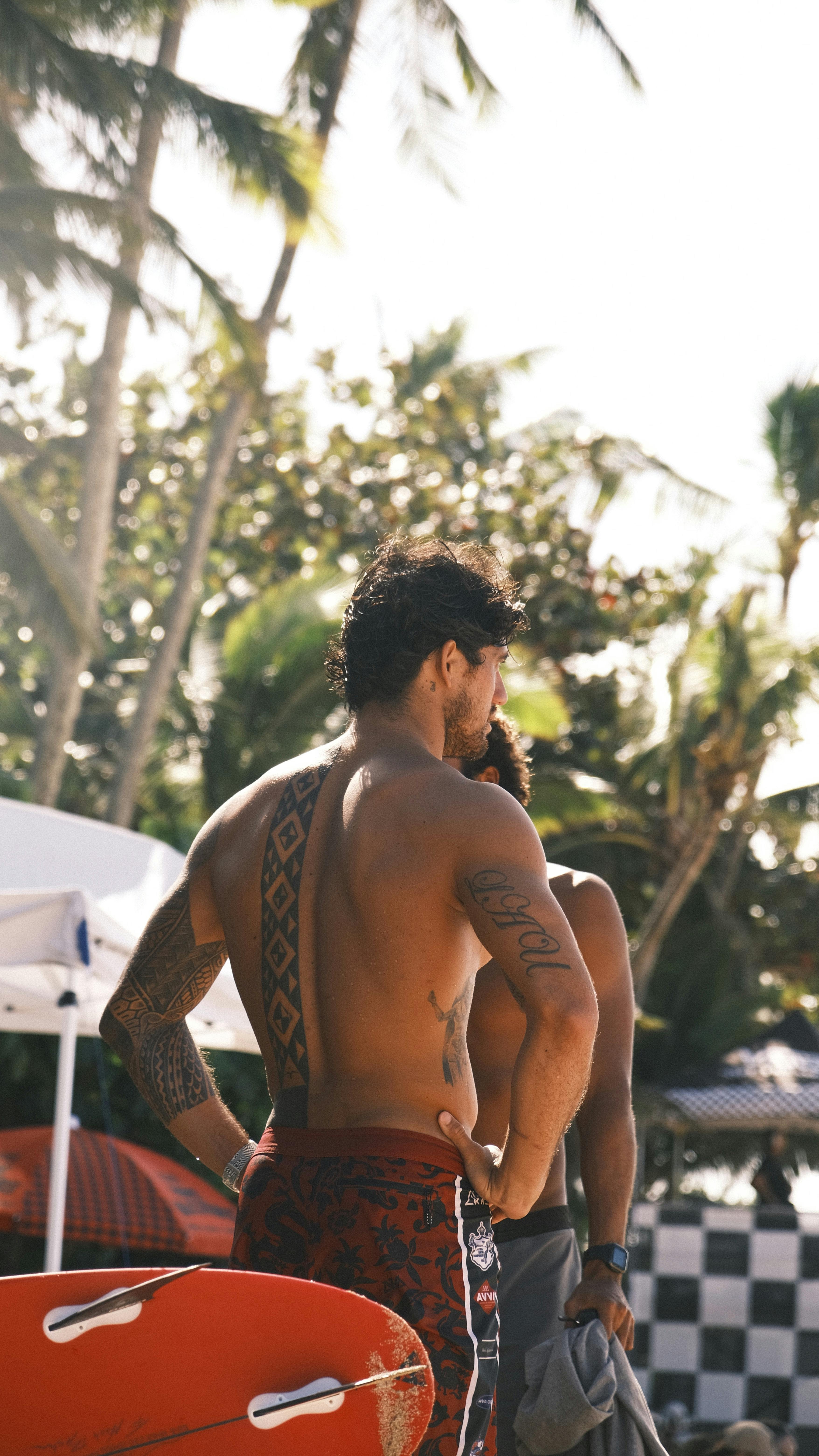 Shirtless Surfer with Tattoos on a Sunny Beach · Free Stock Photo