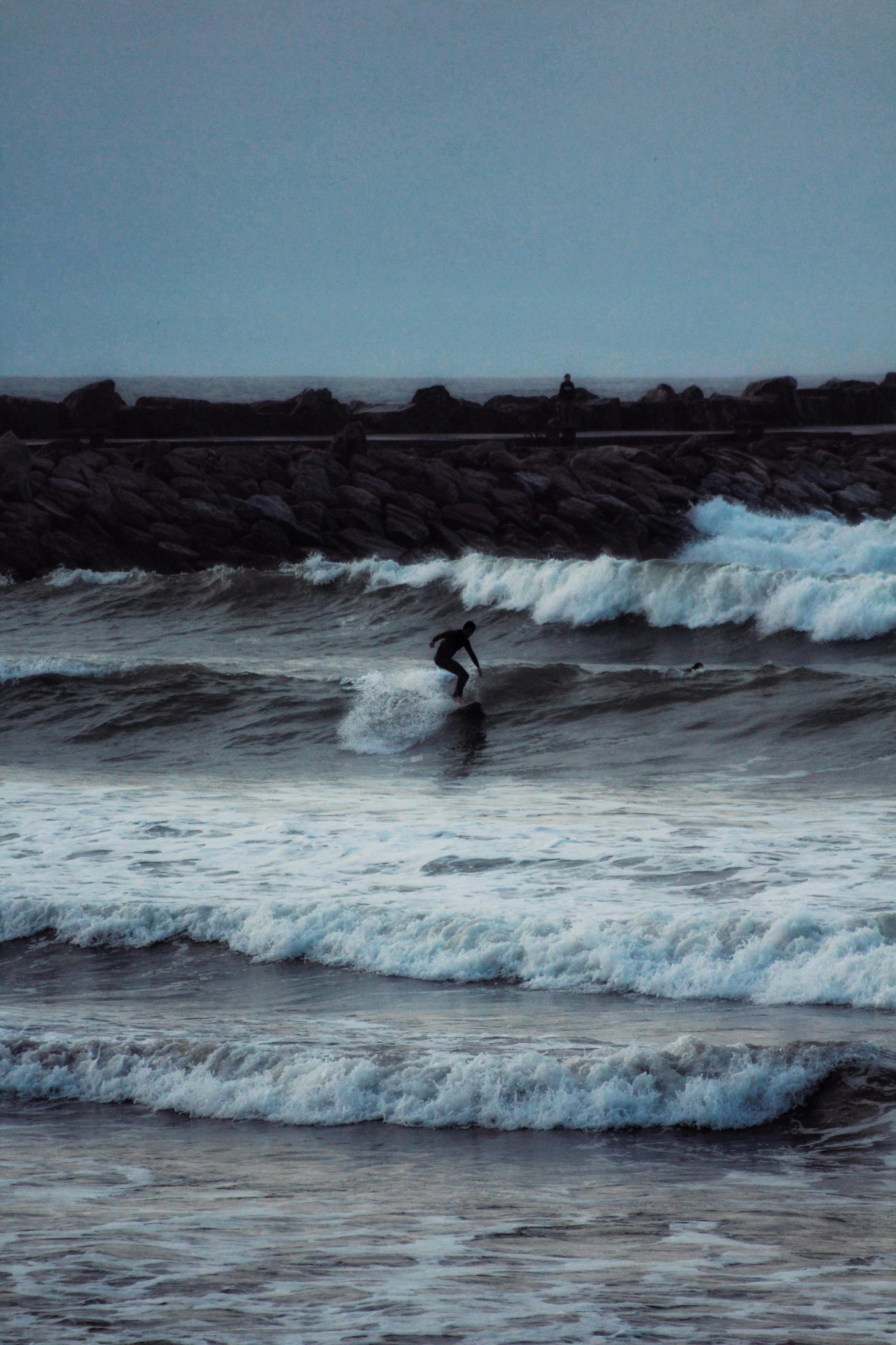 Dynamic Surfing Action at Coastal Breakwater · Free Stock Photo