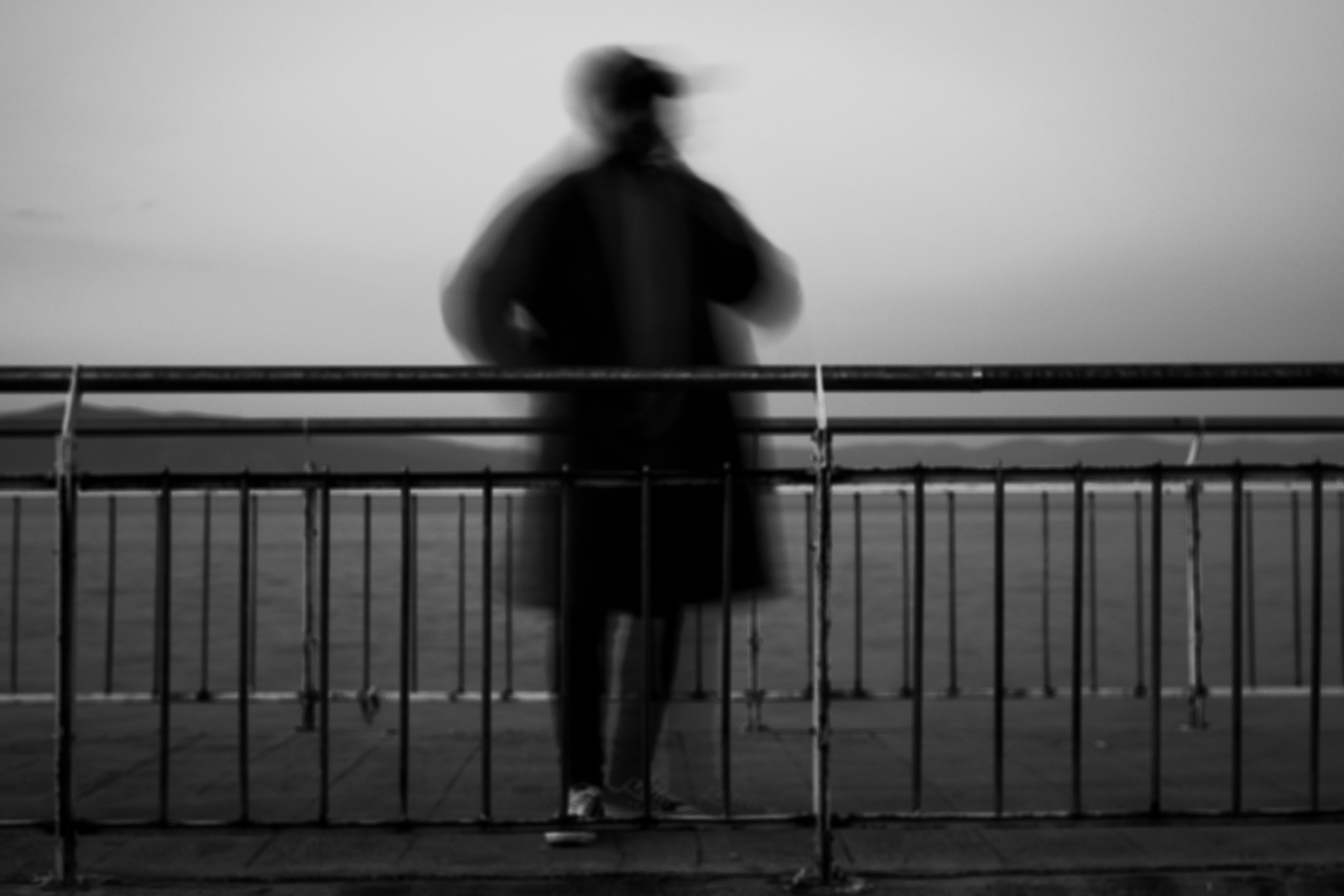 Blurry Figure by Waterfront in Black and White · Free Stock Photo