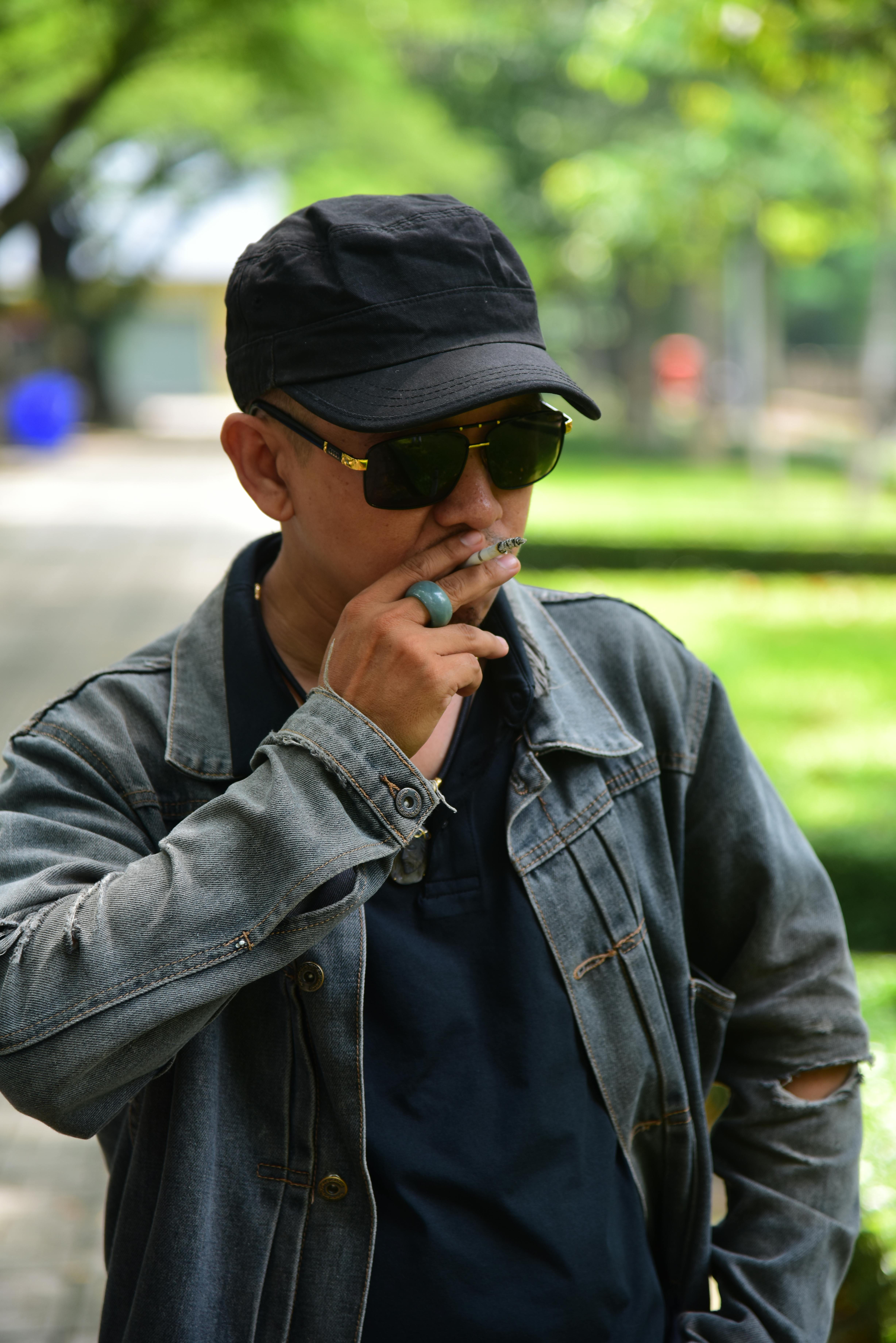 Casual Style Man Smoking Outdoors in Park Setting · Free Stock Photo