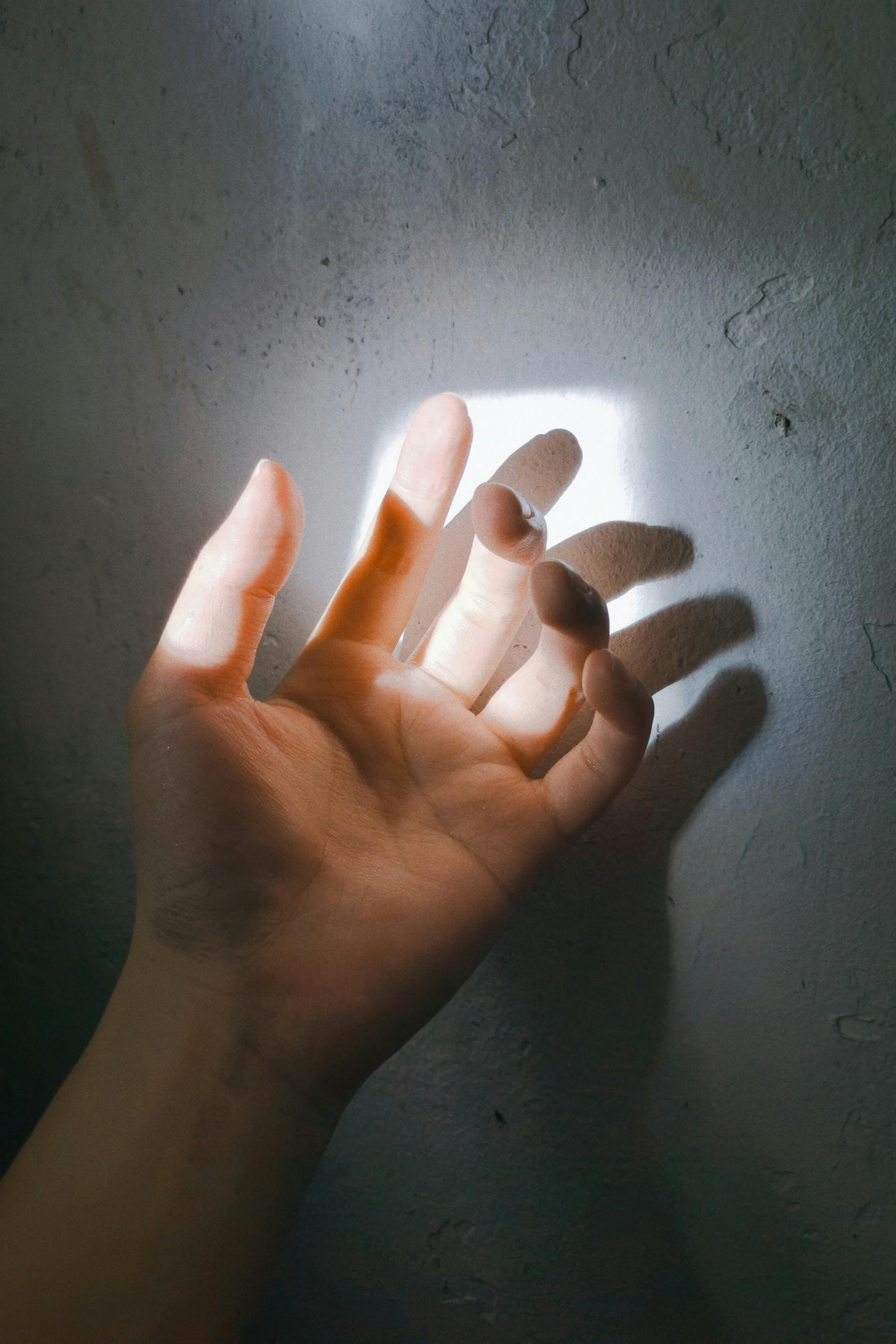 Dramatic Hand Reaching for Light on Wall · Free Stock Photo