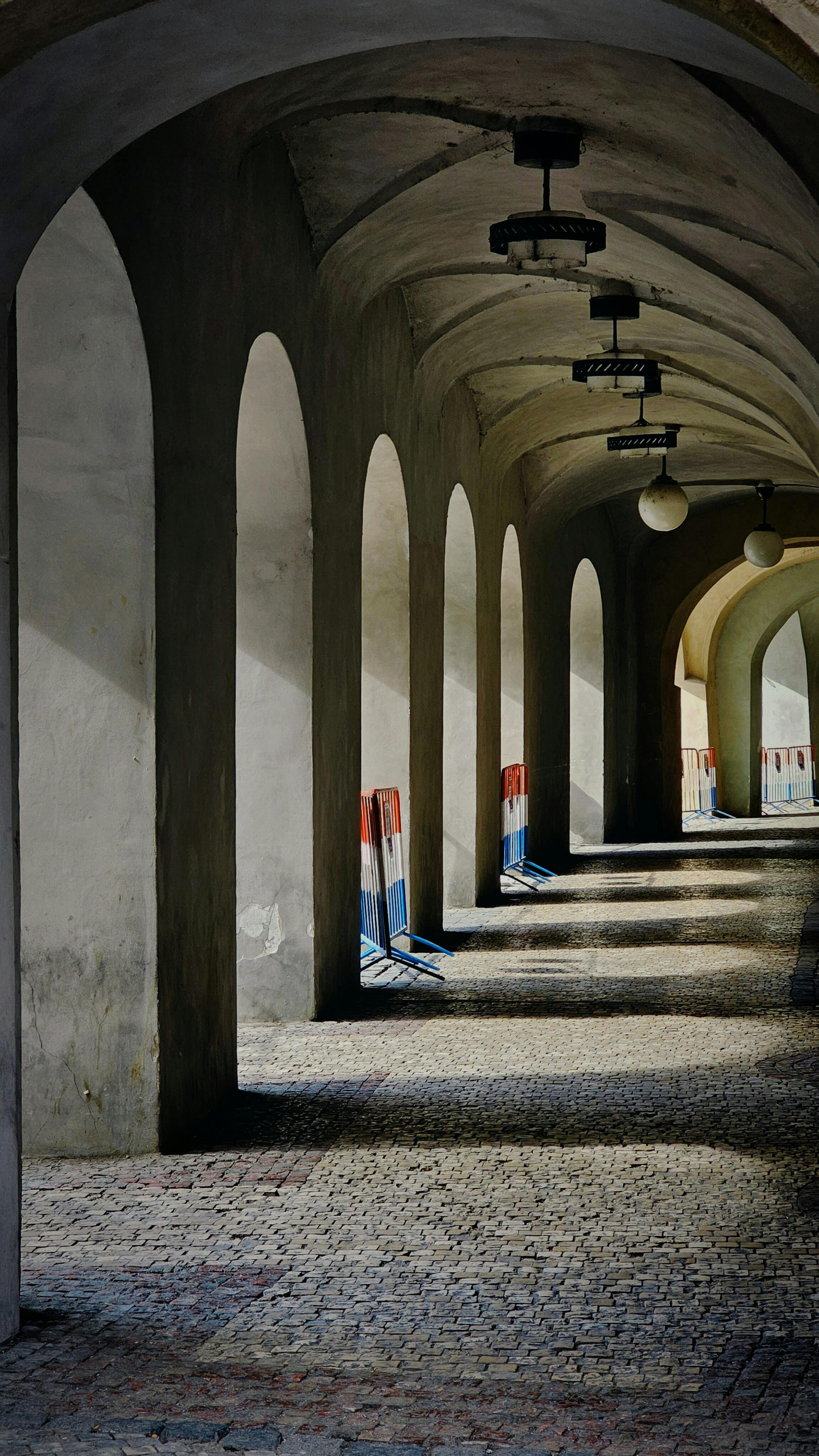 Elegant Arched Corridor with Red Columns · Free Stock Photo