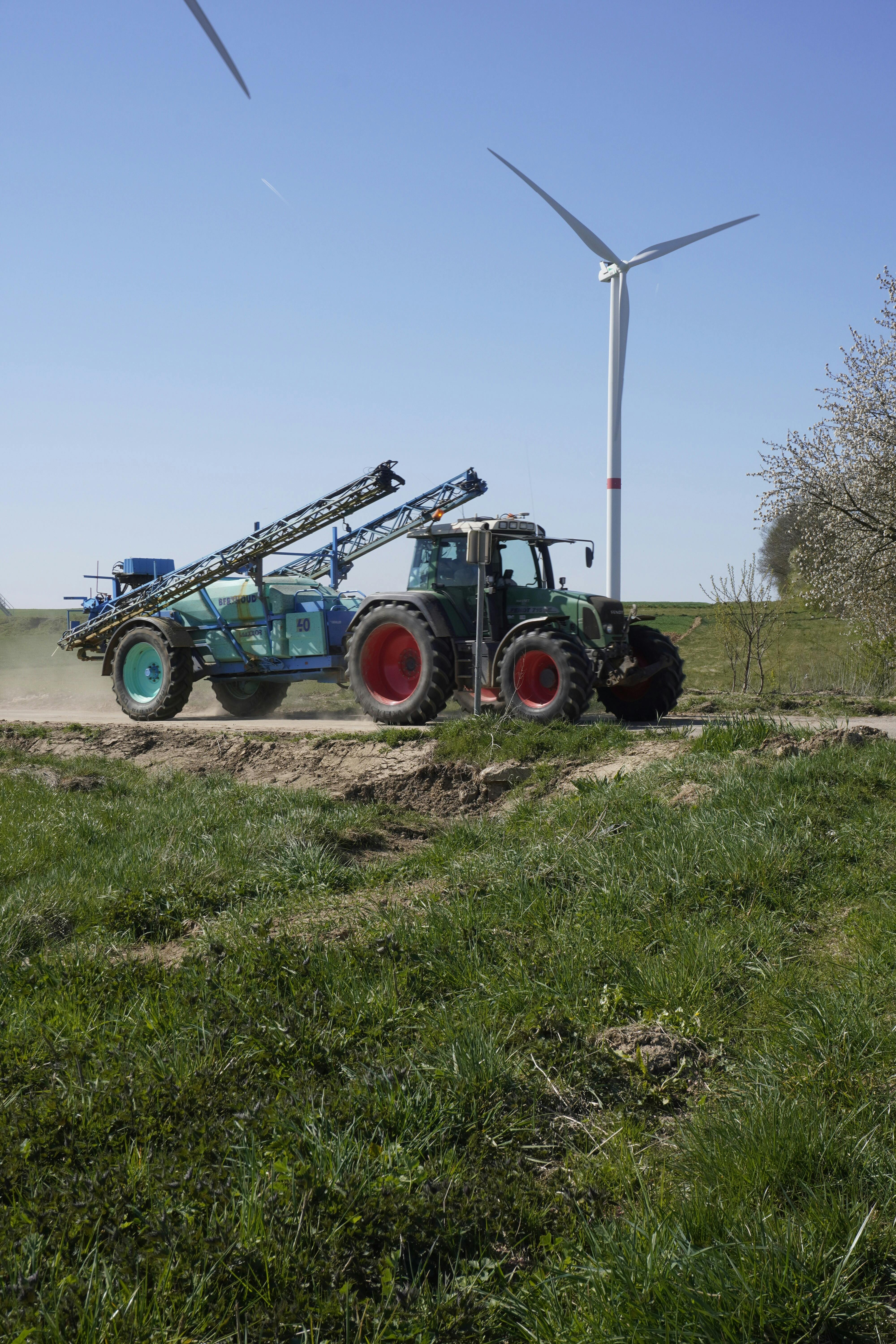 Tractor Spraying Fields Near Wind Turbines · Free Stock Photo