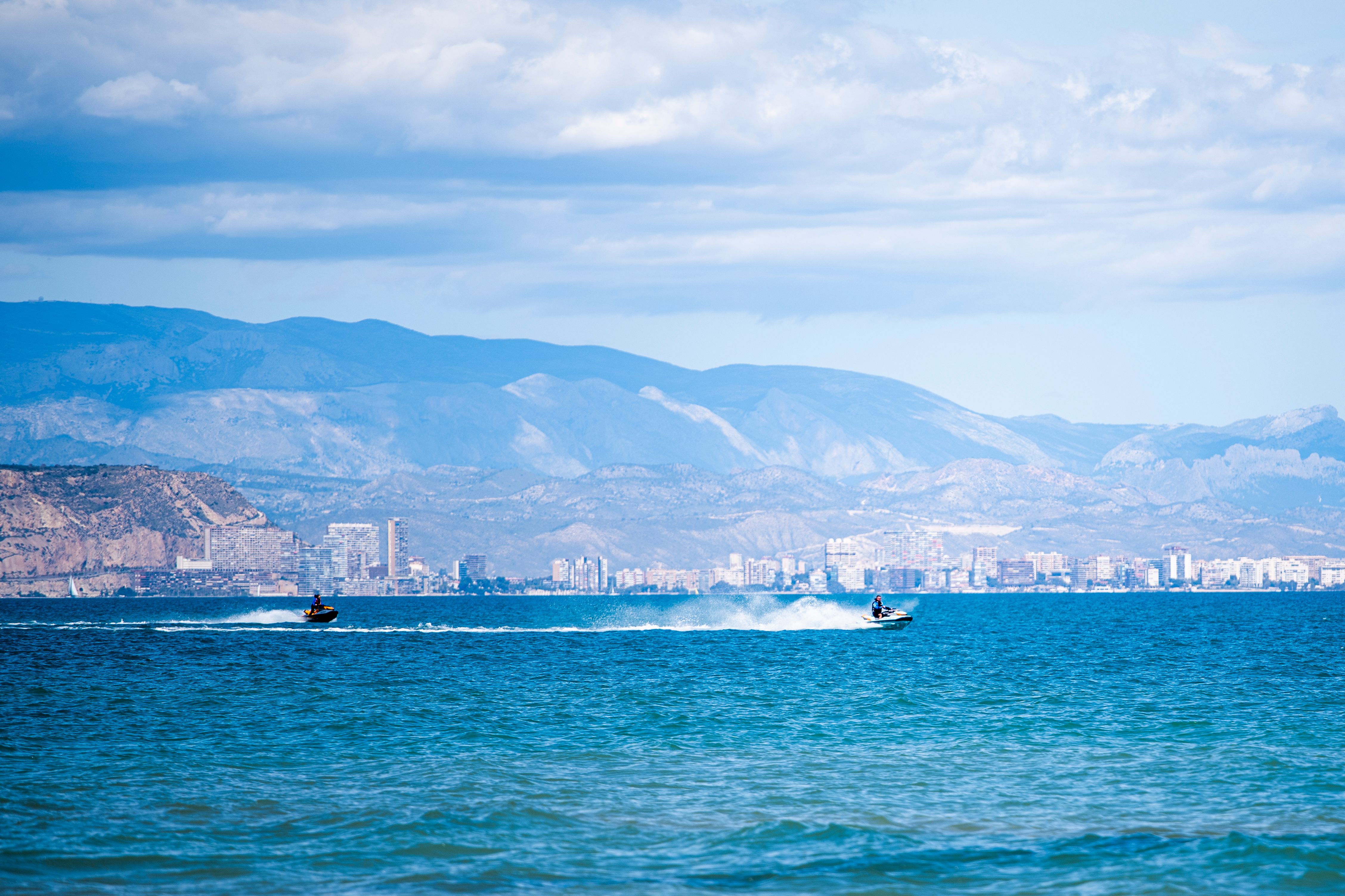 Jet Skis on Scenic Coastal Waters with Mountains · Free Stock Photo