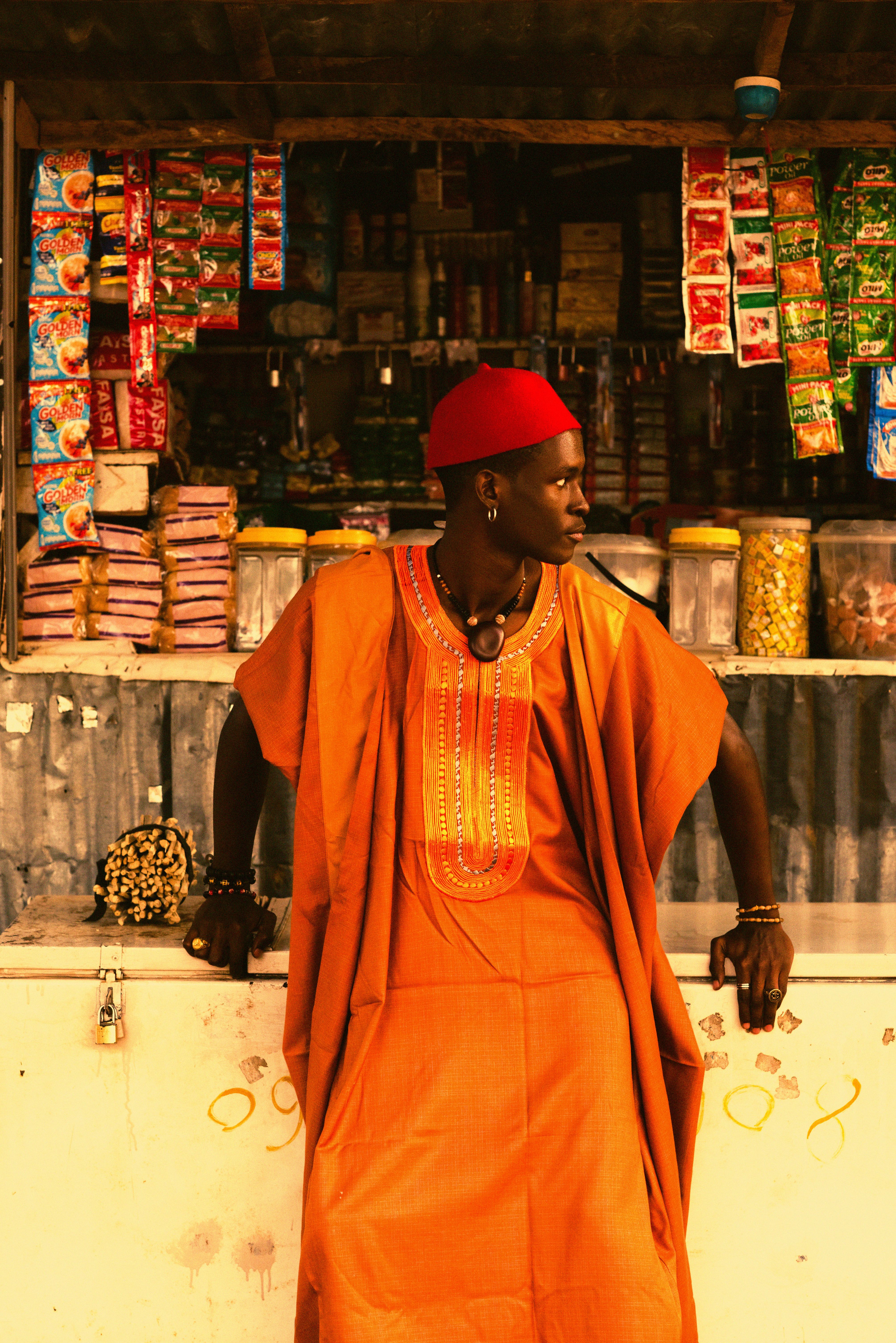 African Vendor in Traditional Garb at Market Stall · Free Stock Photo
