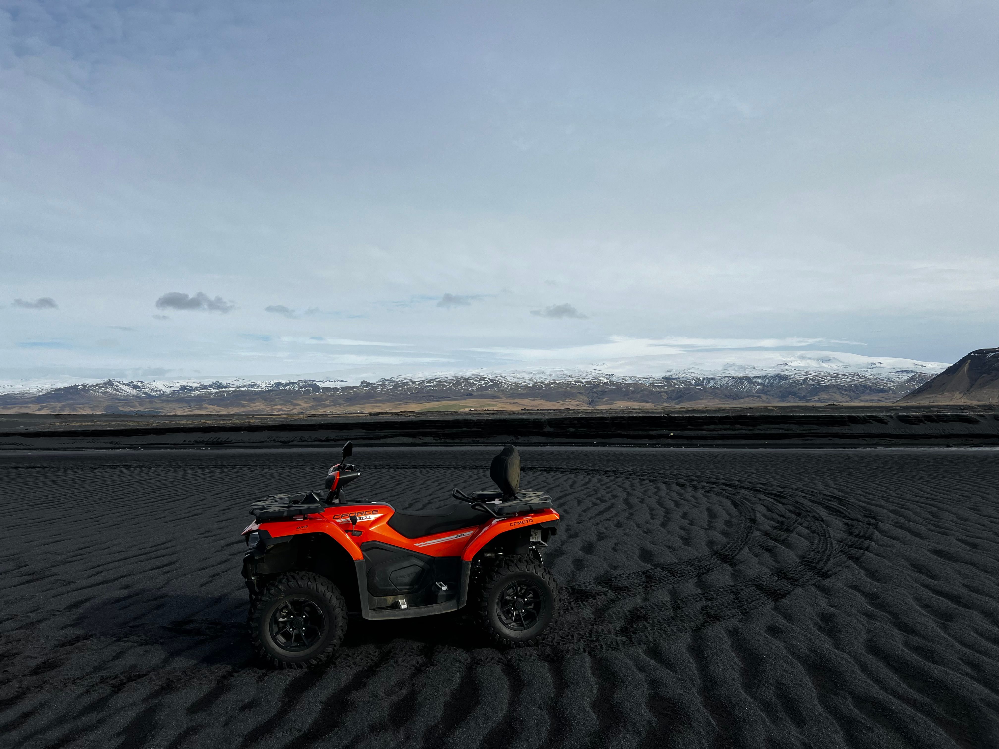 ATV on Black Sand Landscape with Snowy Mountains · Free Stock Photo