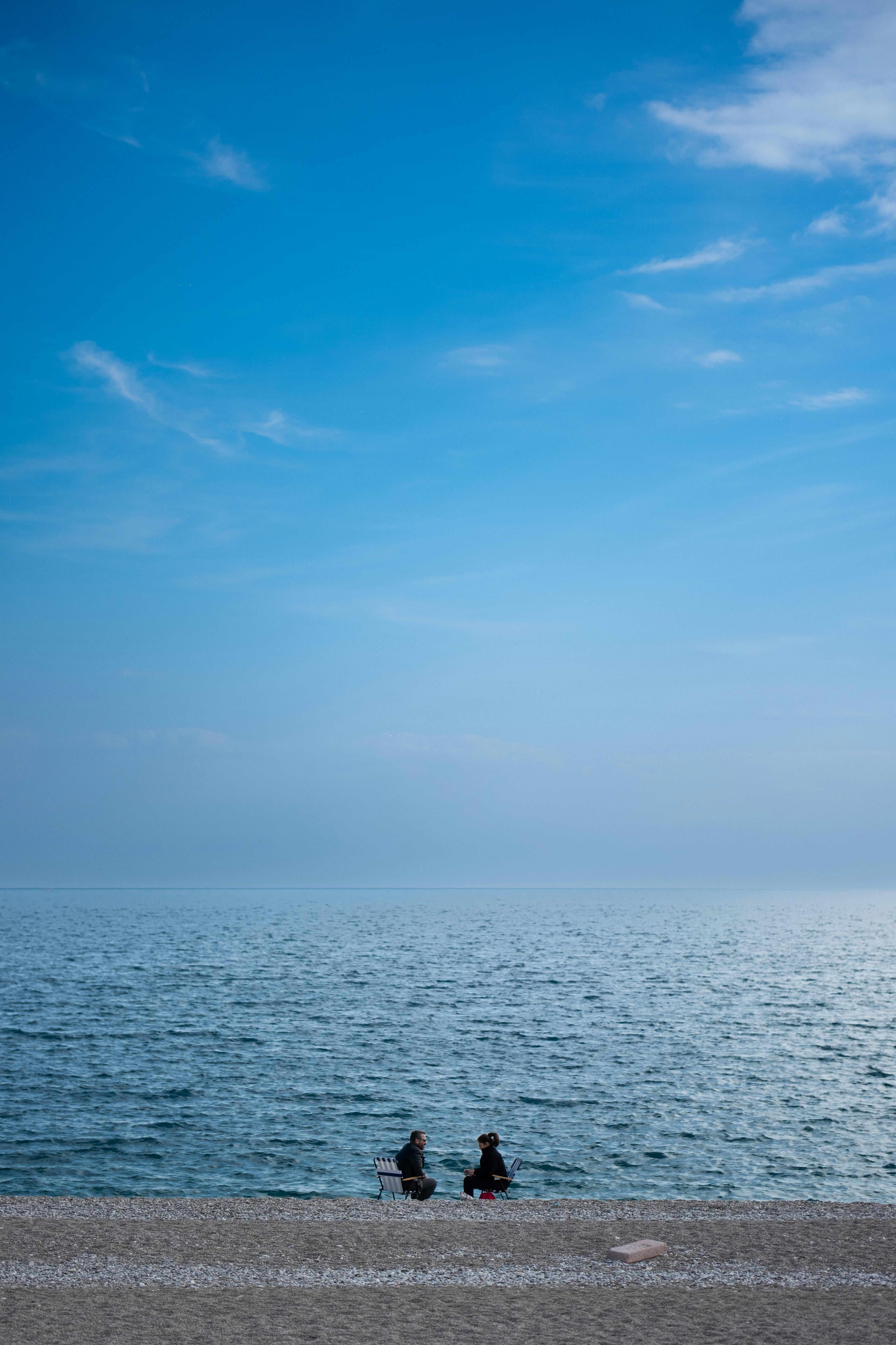 Peaceful Ocean View with Two People on Beach · Free Stock Photo