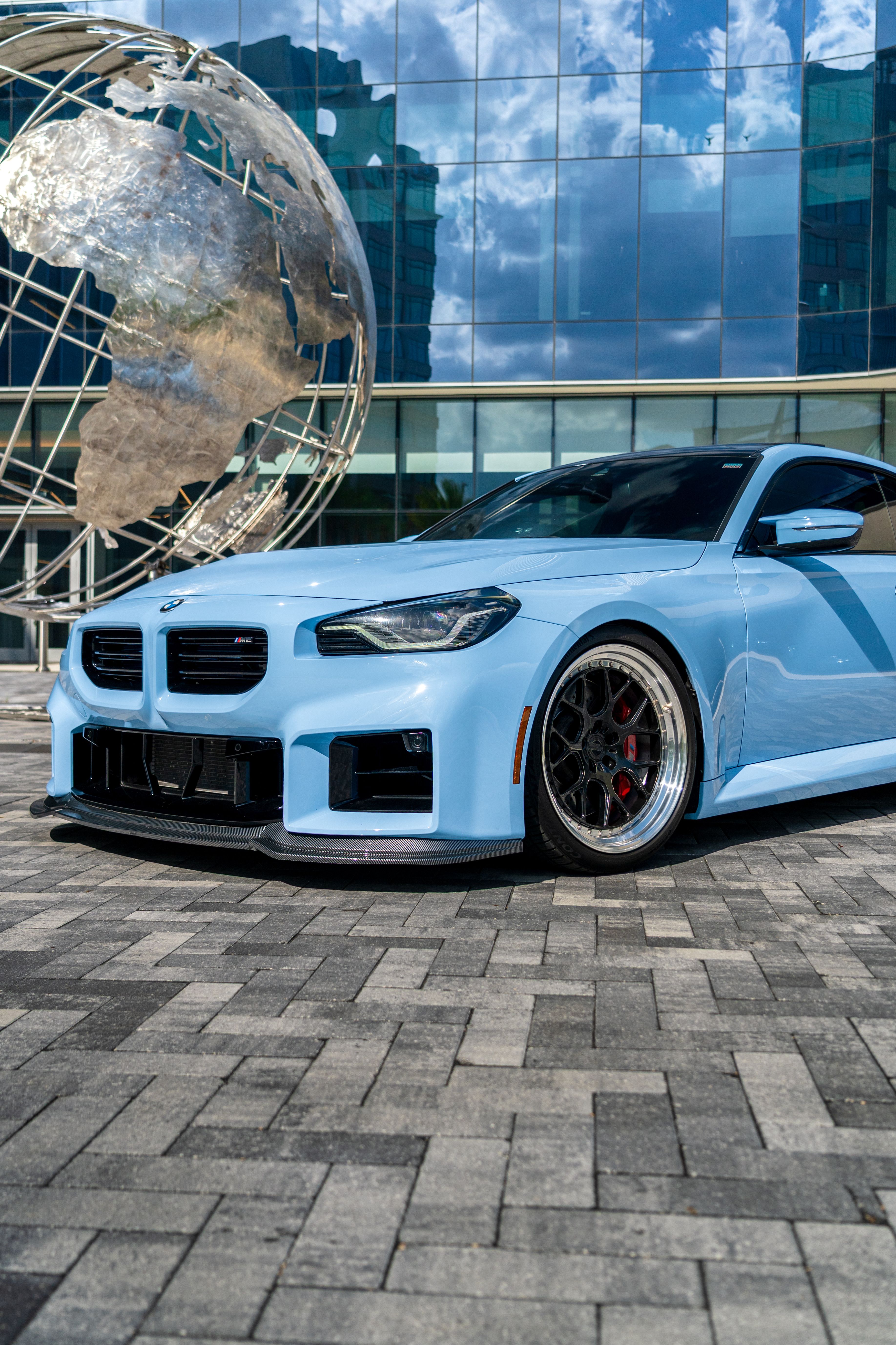 Luxury Blue Car with Globe Sculpture in Cityscape · Free Stock Photo