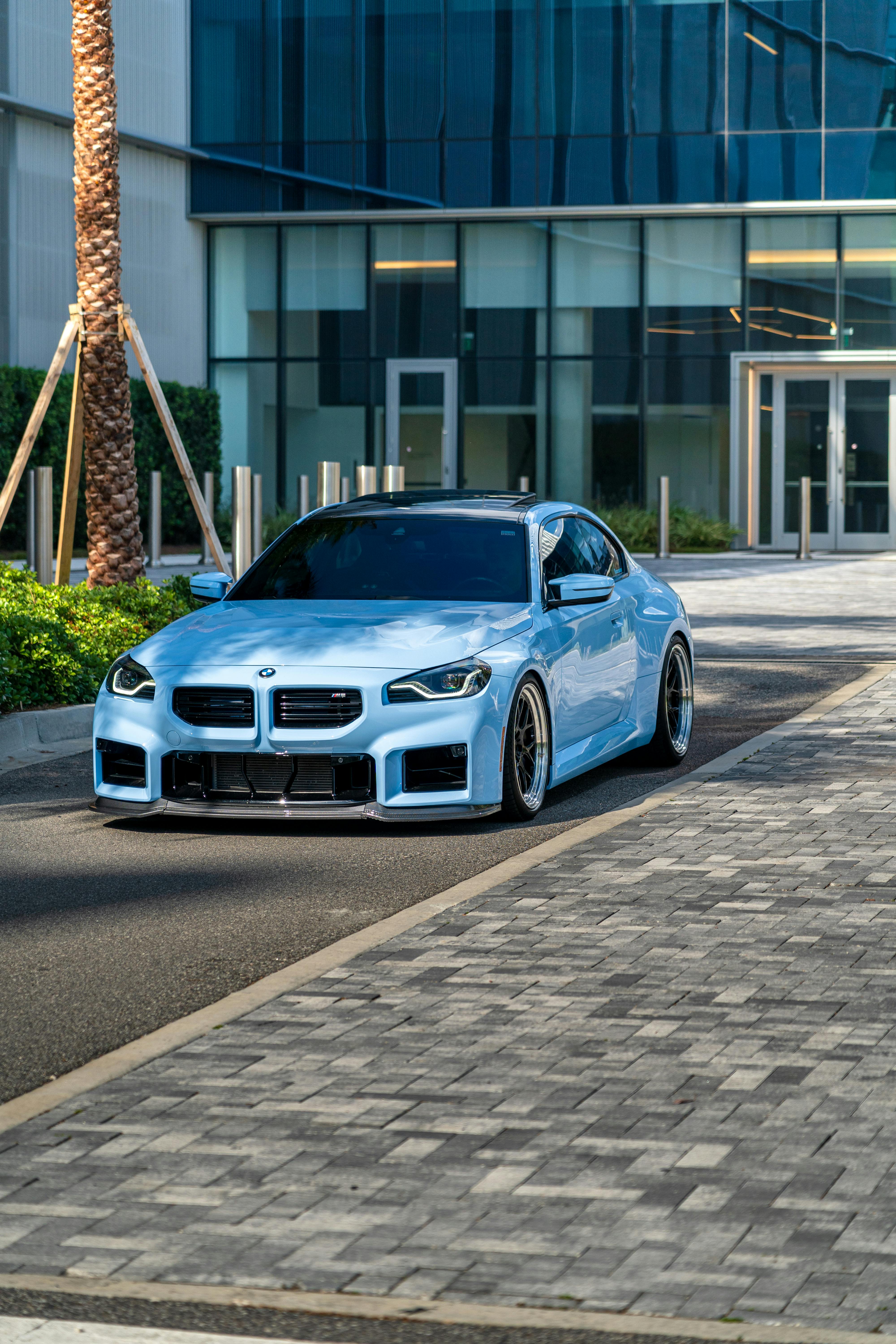 Modern Blue Car Outside Glass Office Building · Free Stock Photo