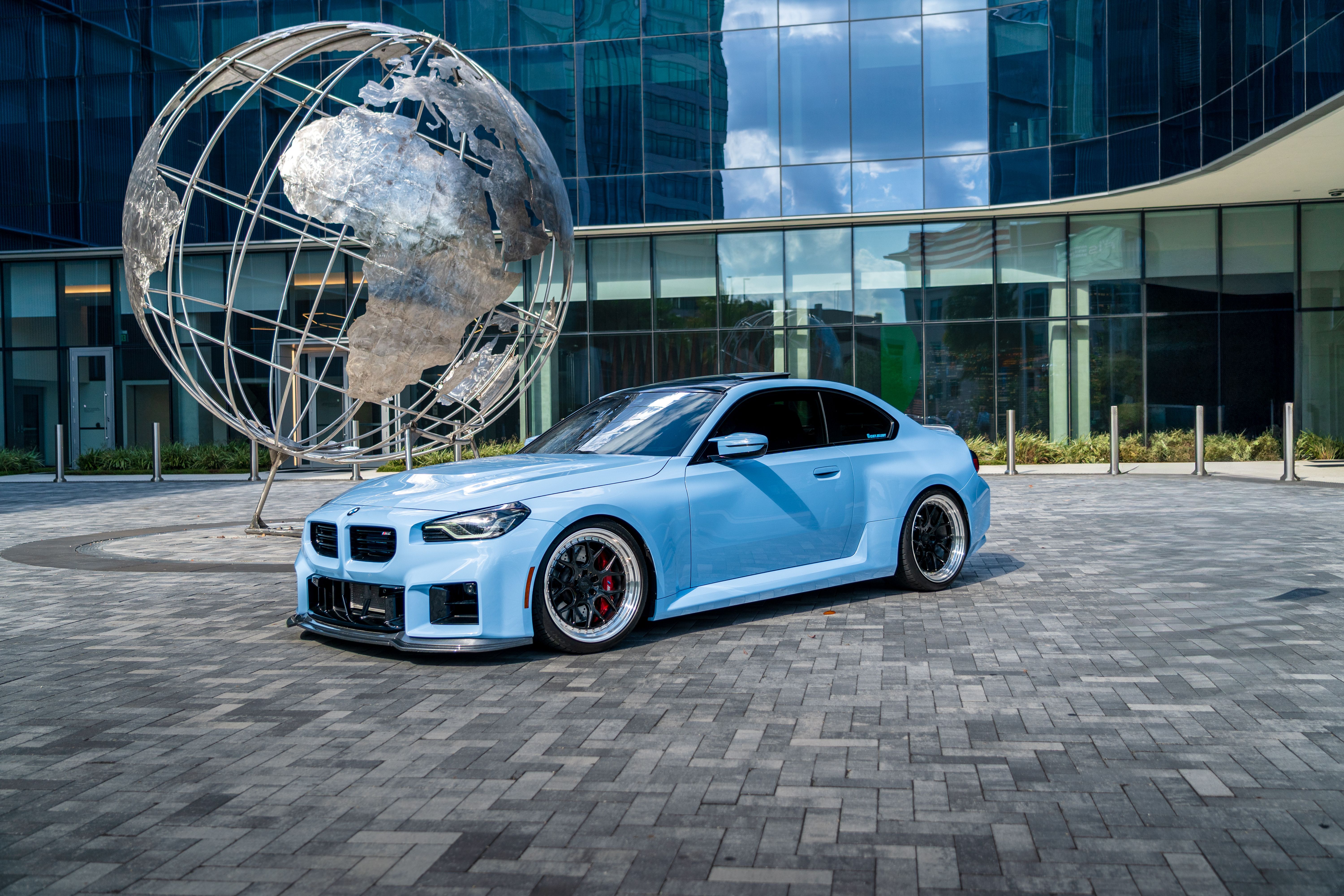 Sleek Blue Car with Globe Sculpture in Modern Plaza · Free Stock Photo