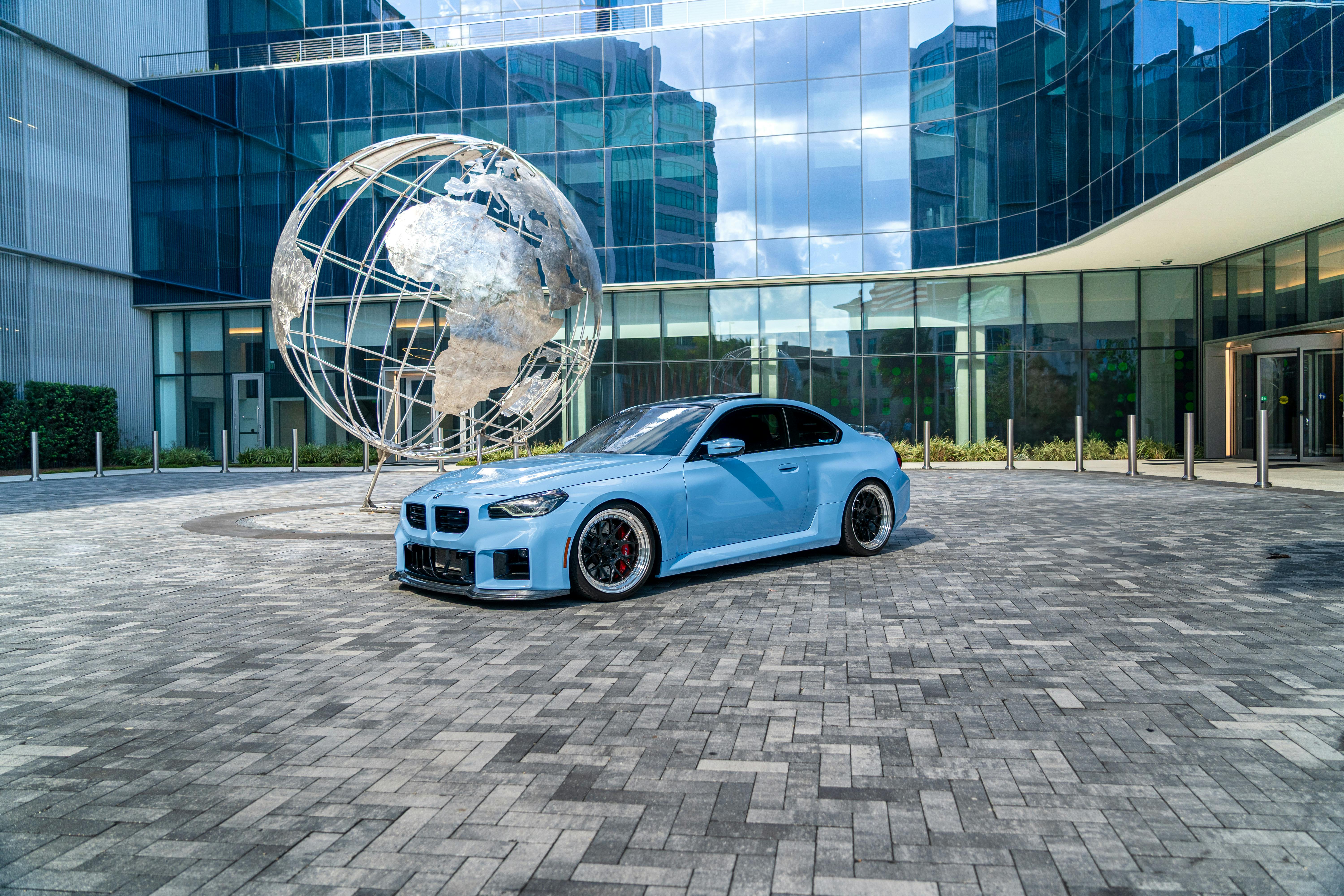 Modern Blue Car with Globe Sculpture in Urban Setting · Free Stock Photo