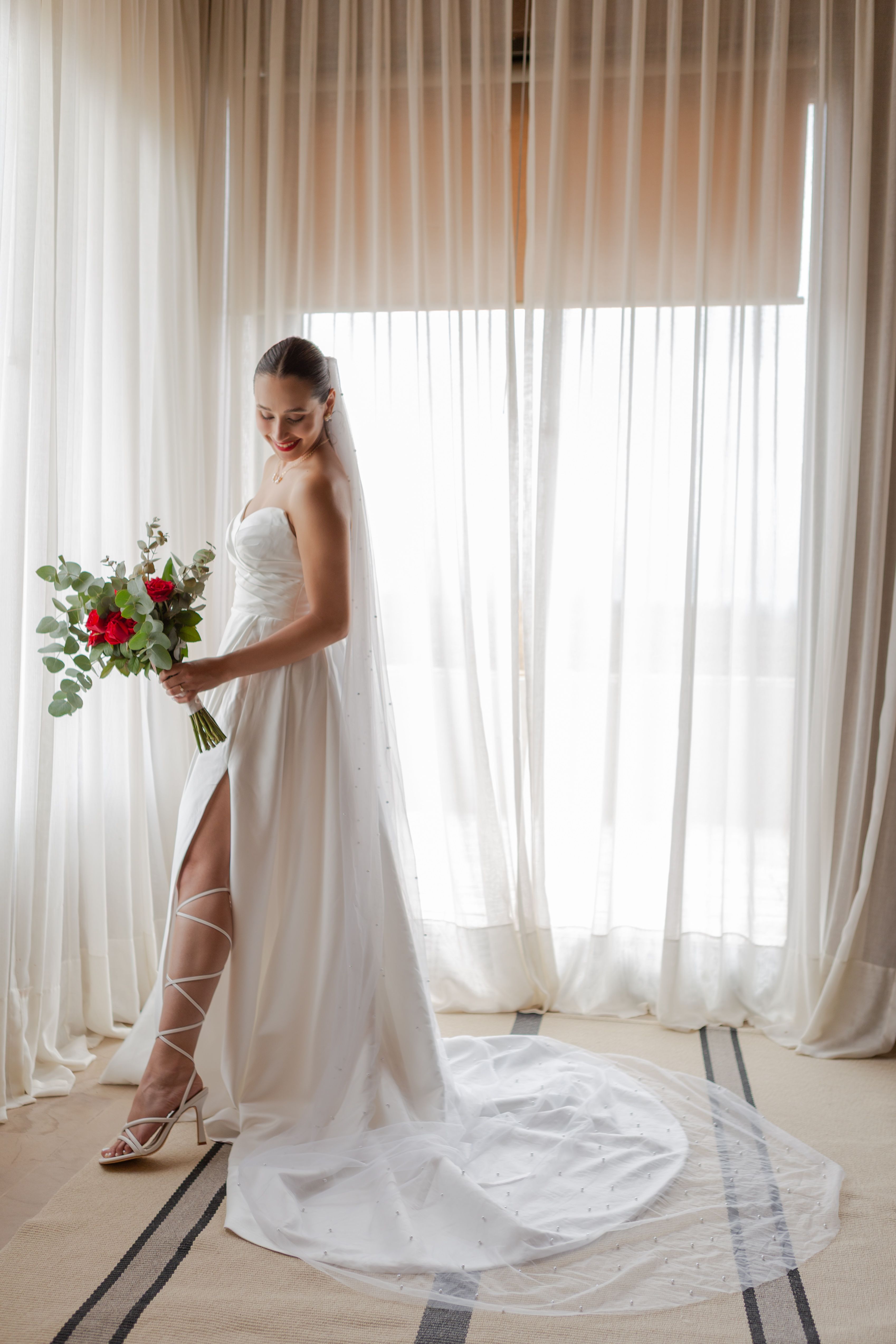 Elegant Bride Posing with Bouquet in Sunlit Room · Free Stock Photo