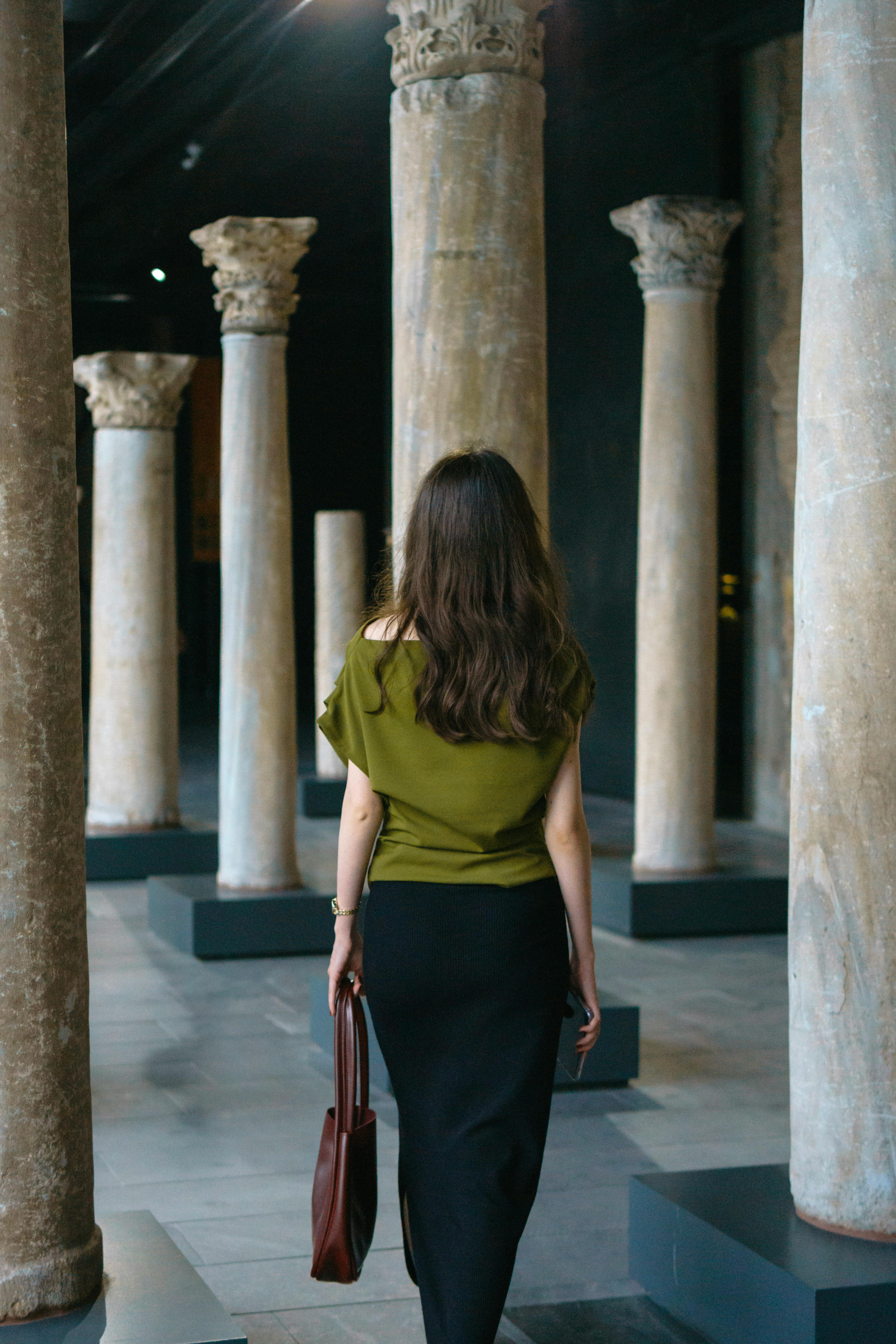 Woman Walking Through Ancient Museum Corridor · Free Stock Photo