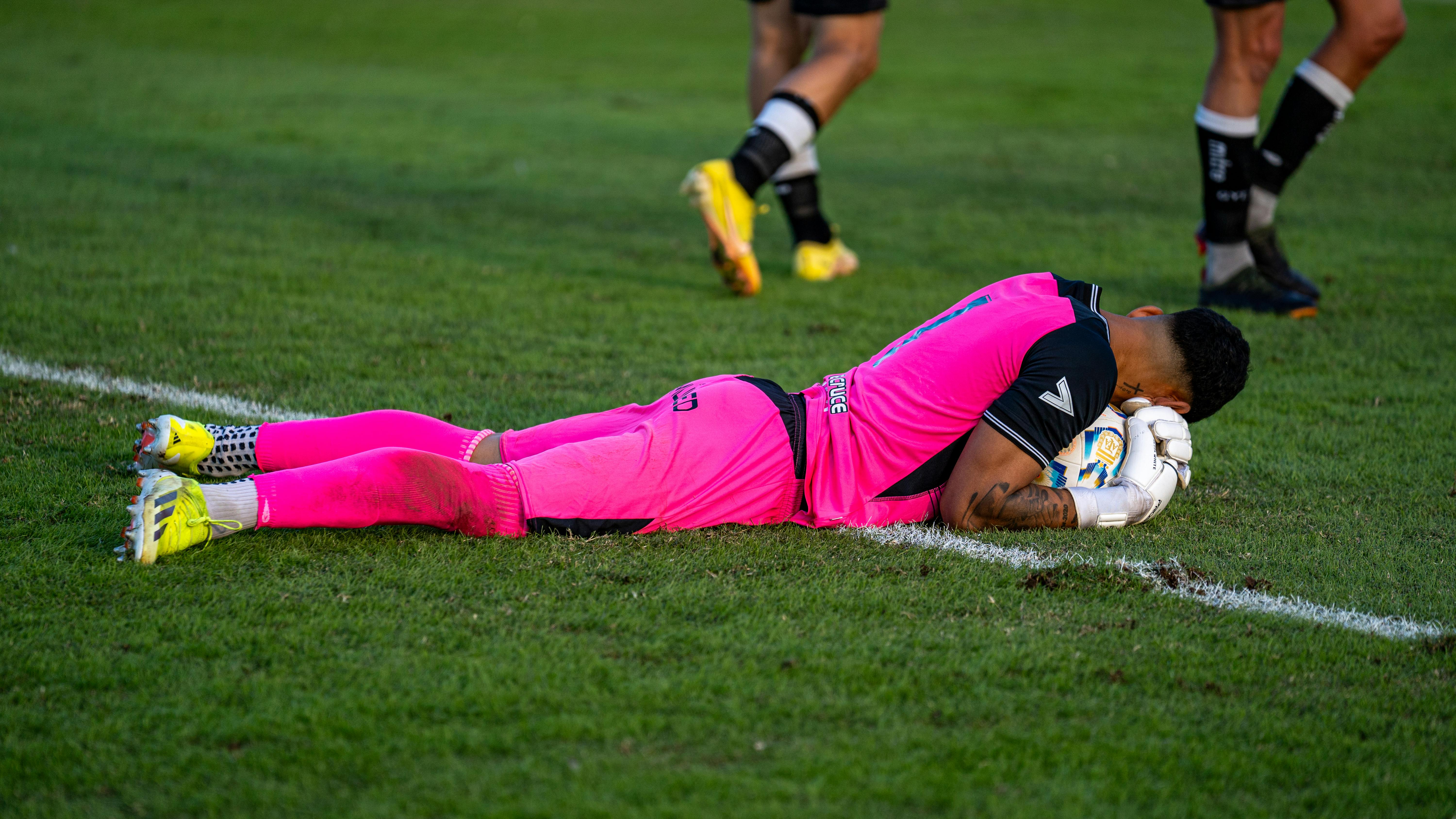 Soccer Goalie in Pink Kit Lying on Field in Defeat · Free Stock Photo