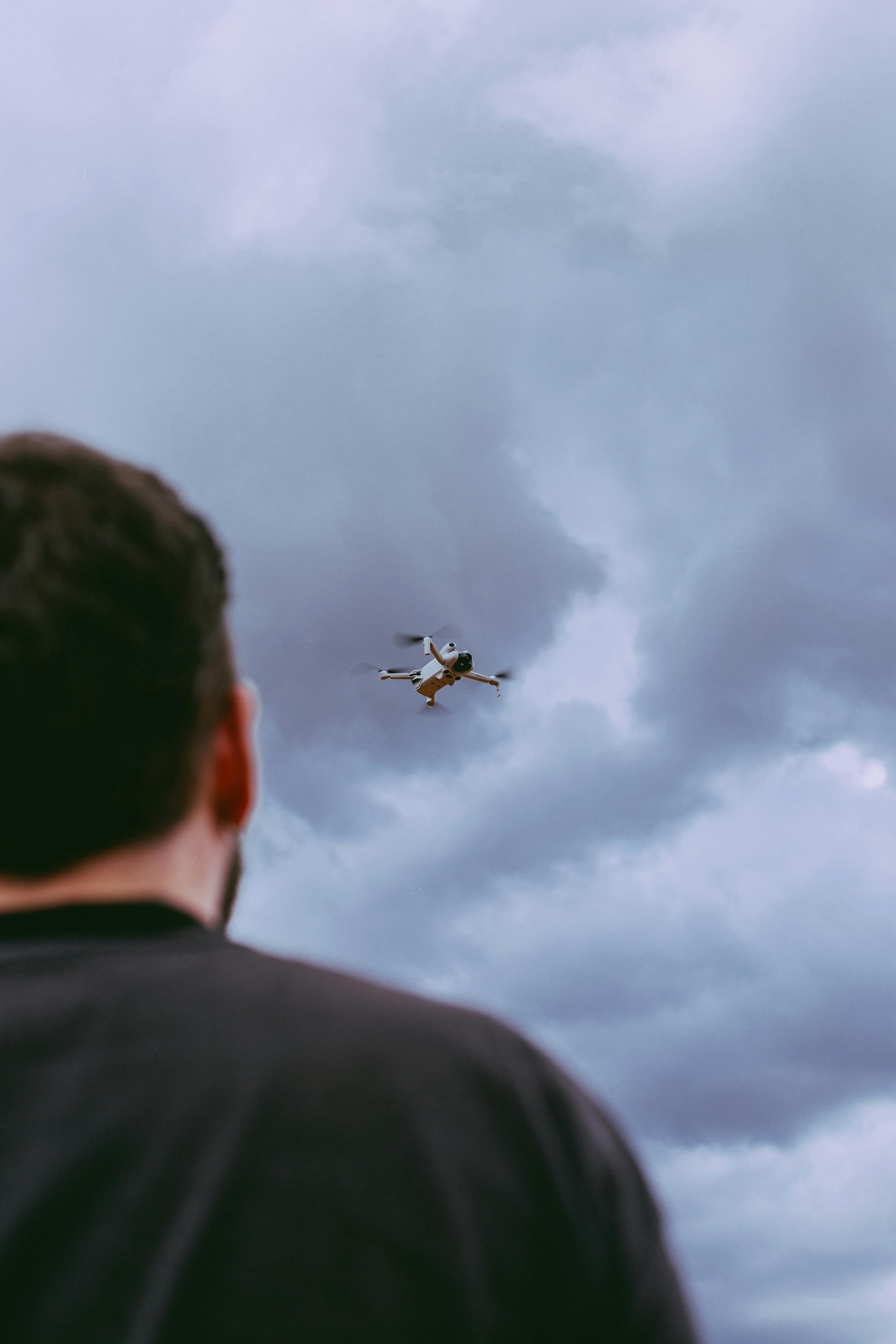 Man Watching Drone Fly Through Cloudy Sky · Free Stock Photo