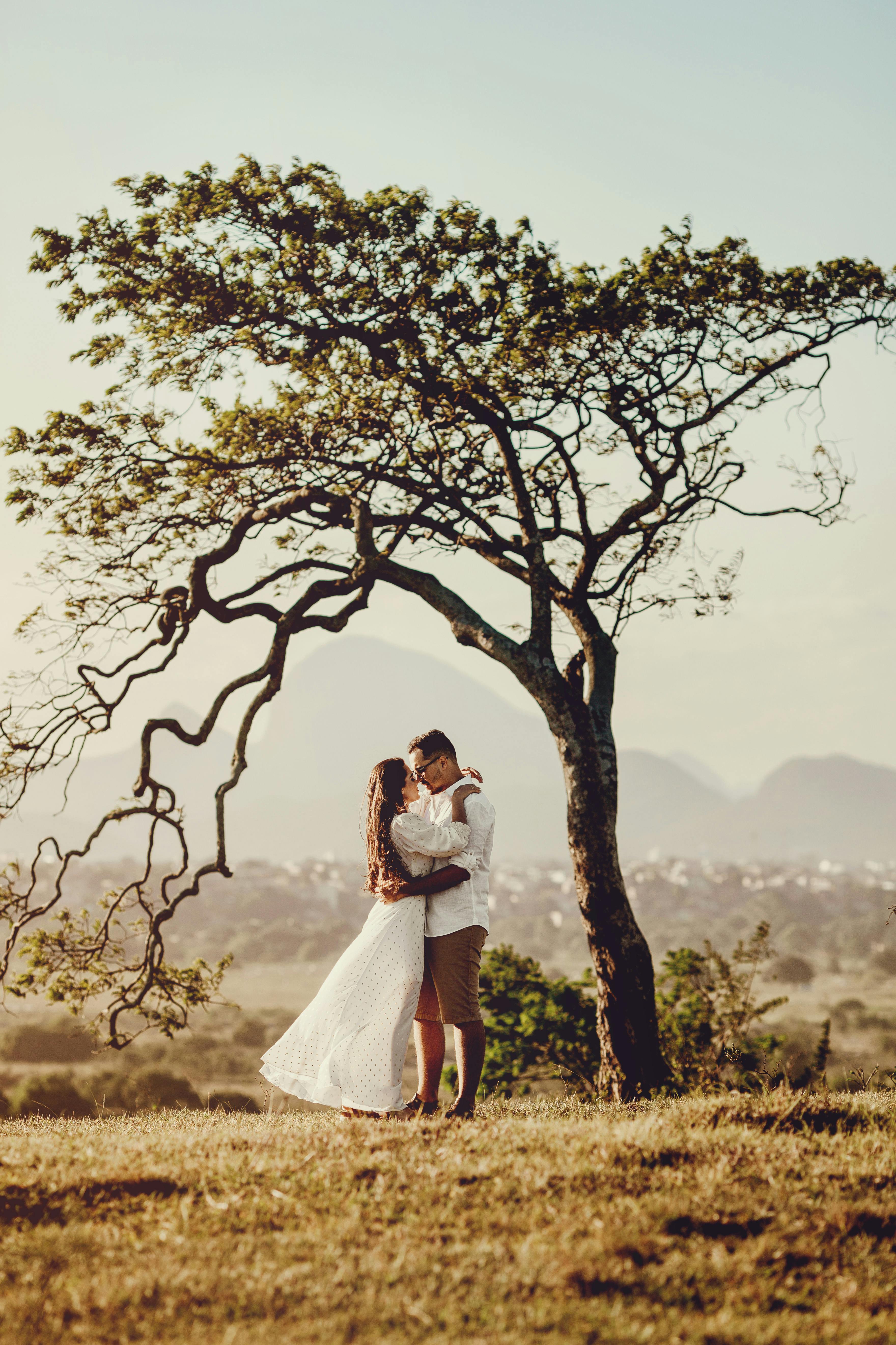 Man and Woman in Holding Each other Standing Beside Tree · Free Stock Photo