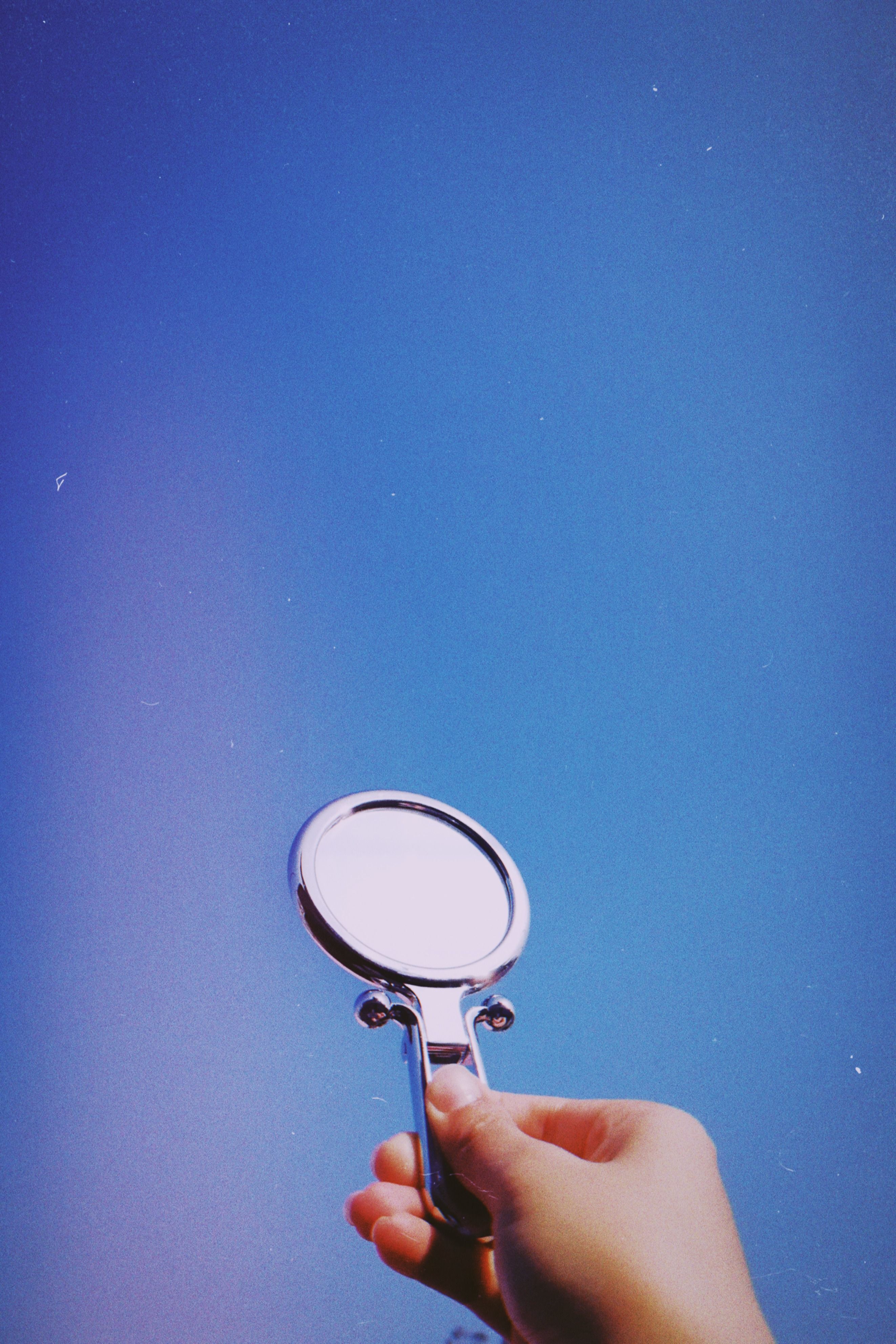 Person Holding Hand Mirror Against Vibrant Blue Sky · Free Stock Photo