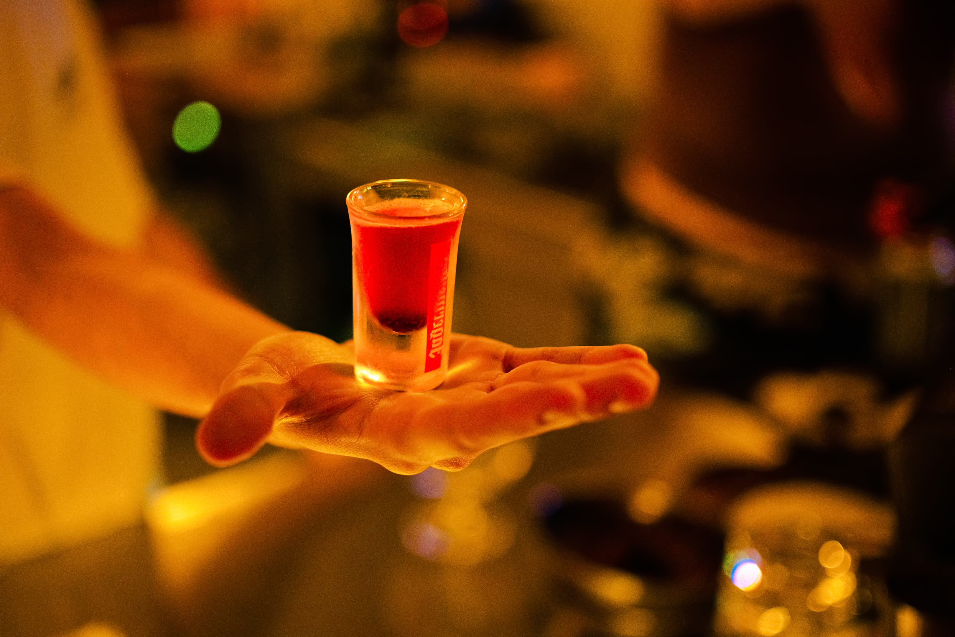 Vibrant Red Cocktail Shot in Hand at Bar · Free Stock Photo