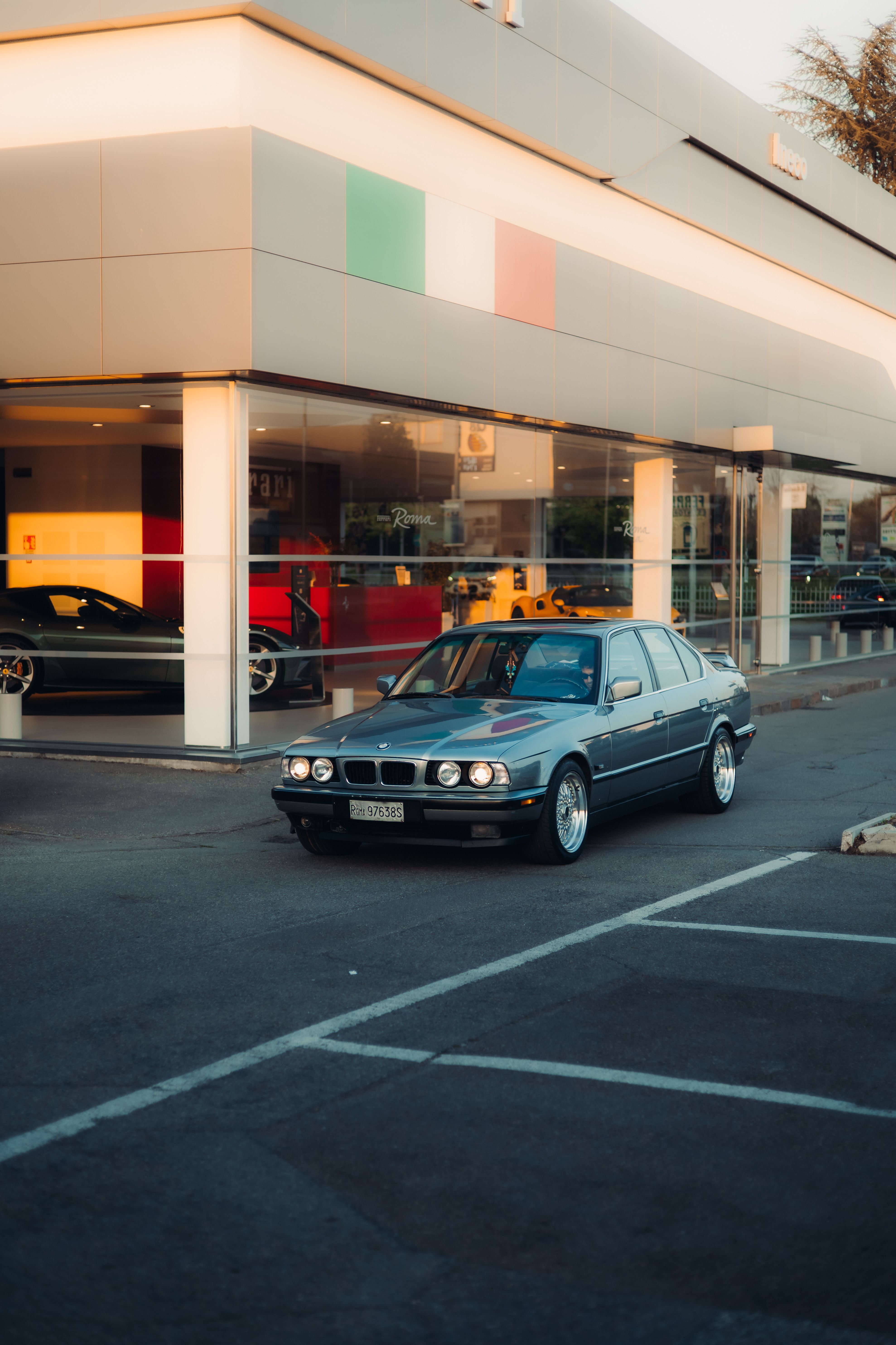 Vintage Car Parked Outside Modern Car Showroom · Free Stock Photo