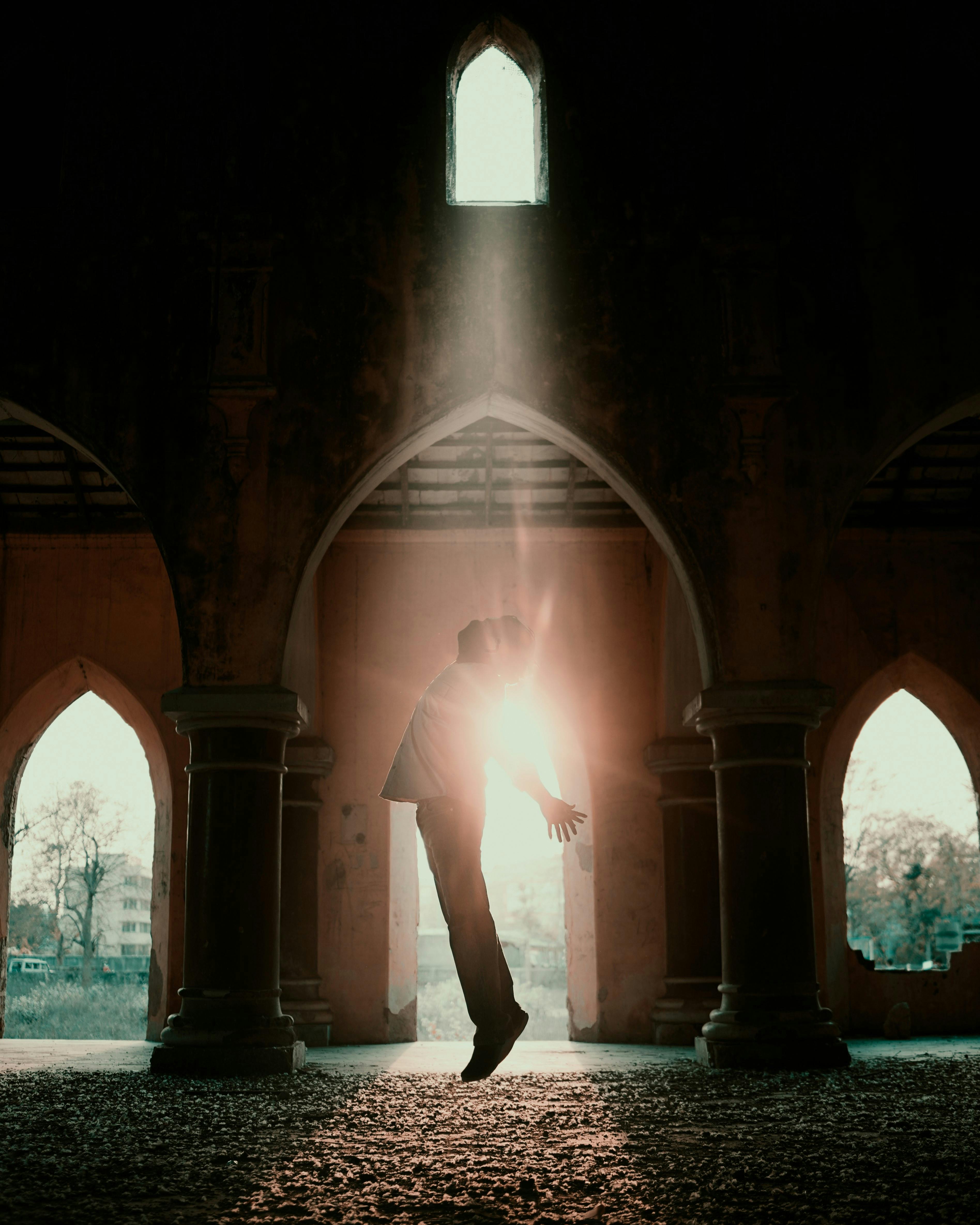 Silhouette of Levitation Inside Sunlit Arched Building · Free Stock Photo