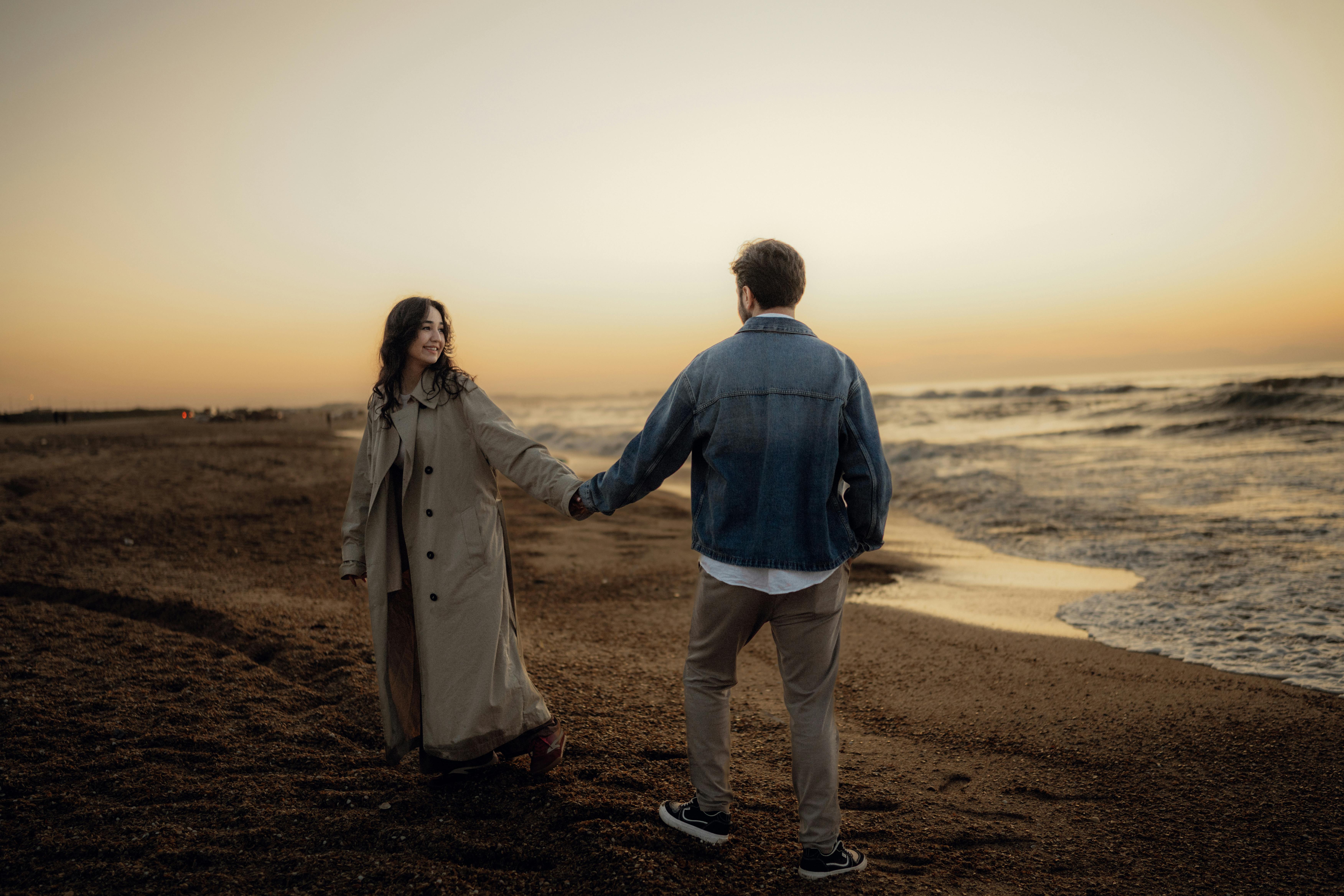 Romantic Couple Strolling on Sunset Beach · Free Stock Photo