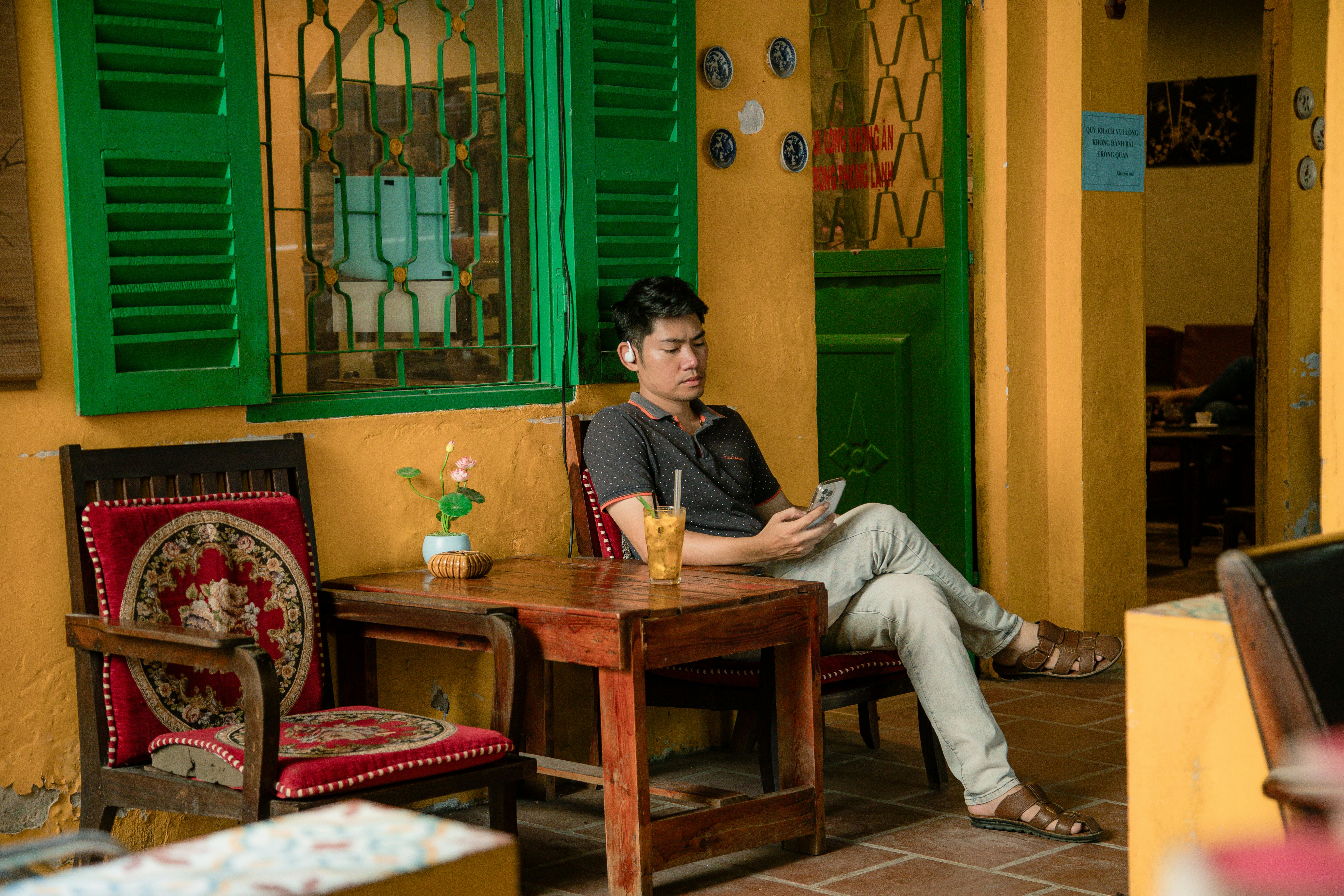 Relaxed Café Ambiance with Man Using Smartphone · Free Stock Photo