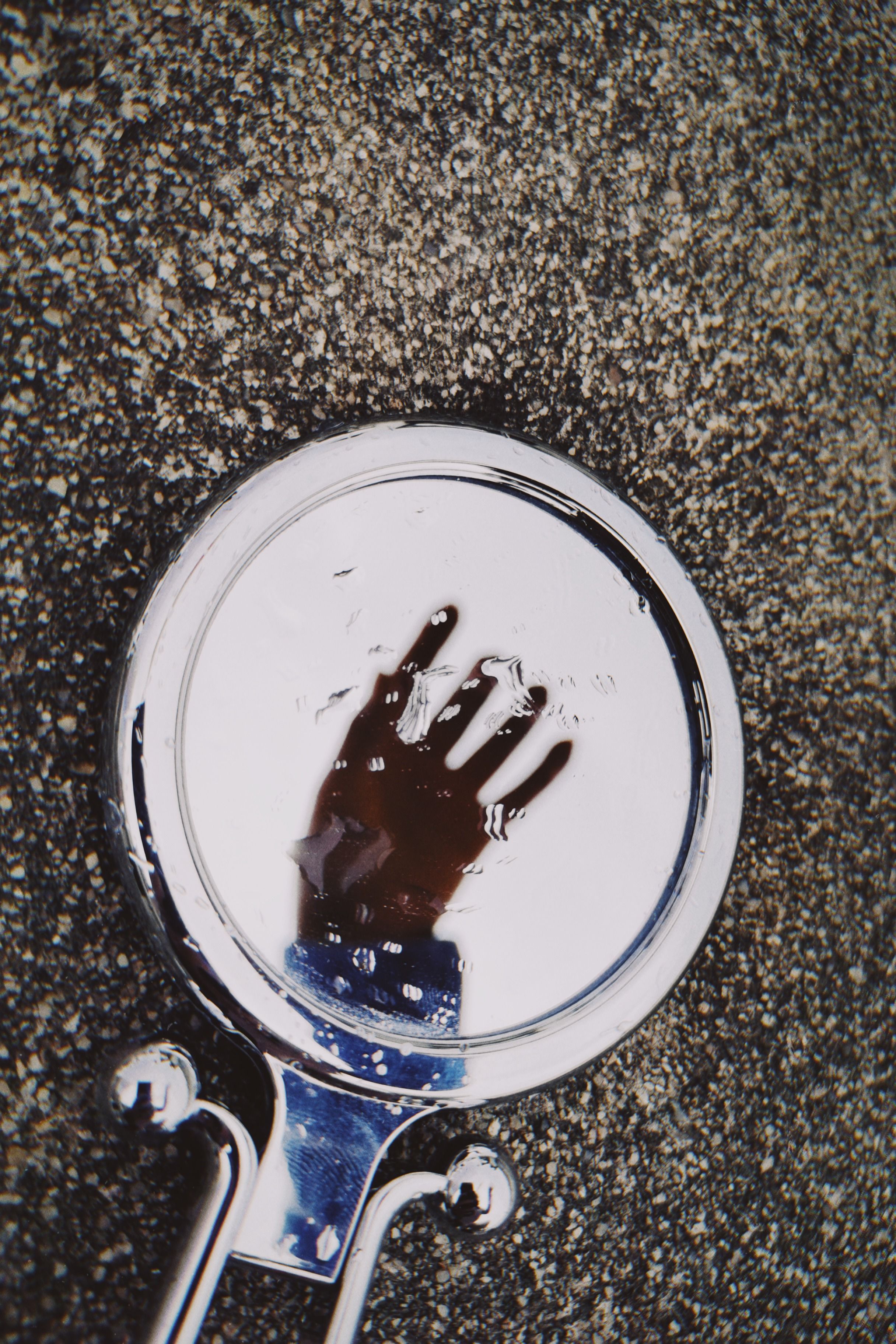Reflection of hand in round mirror on stone surface · Free Stock Photo