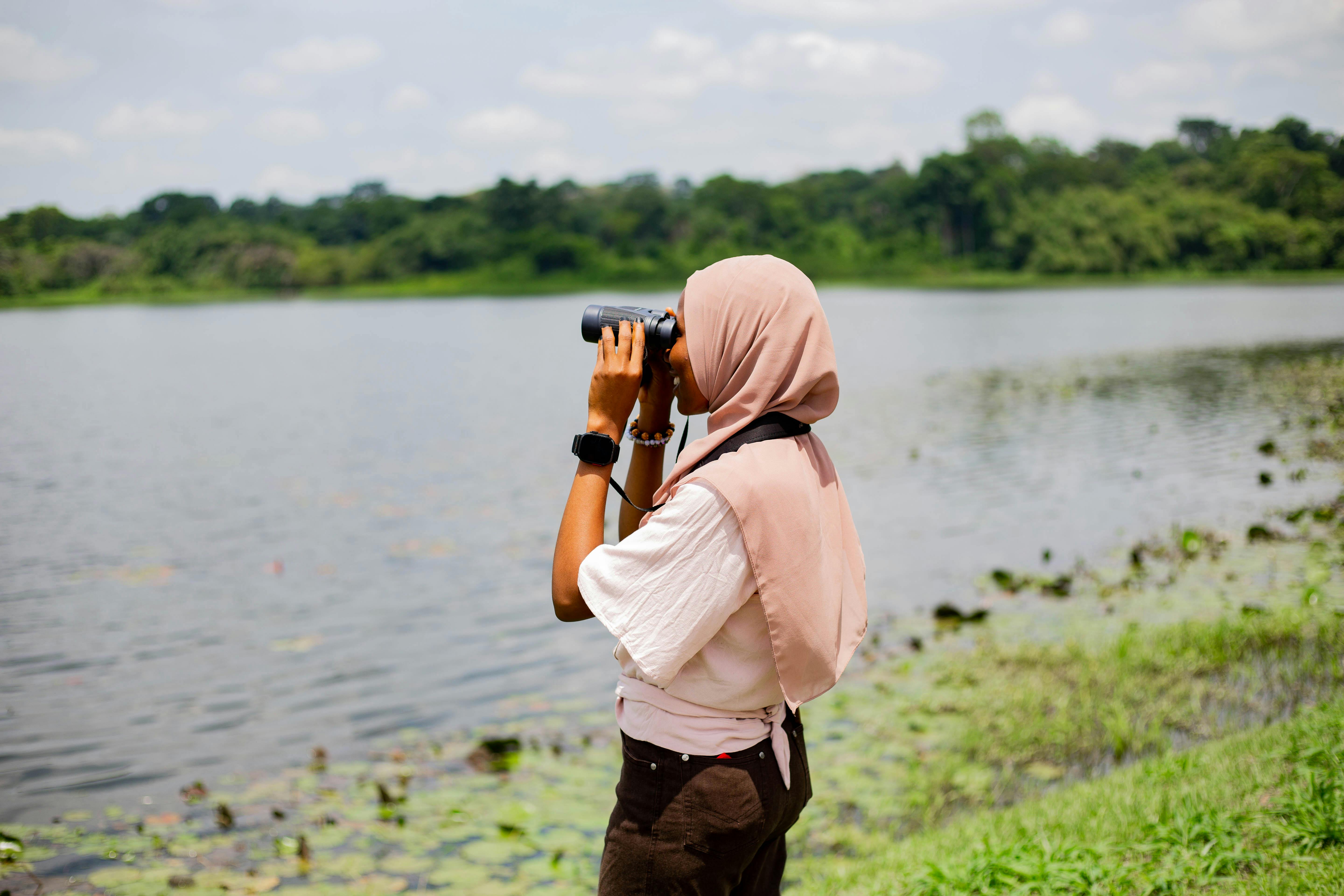 Woman Birdwatching by Tranquil Lake · Free Stock Photo