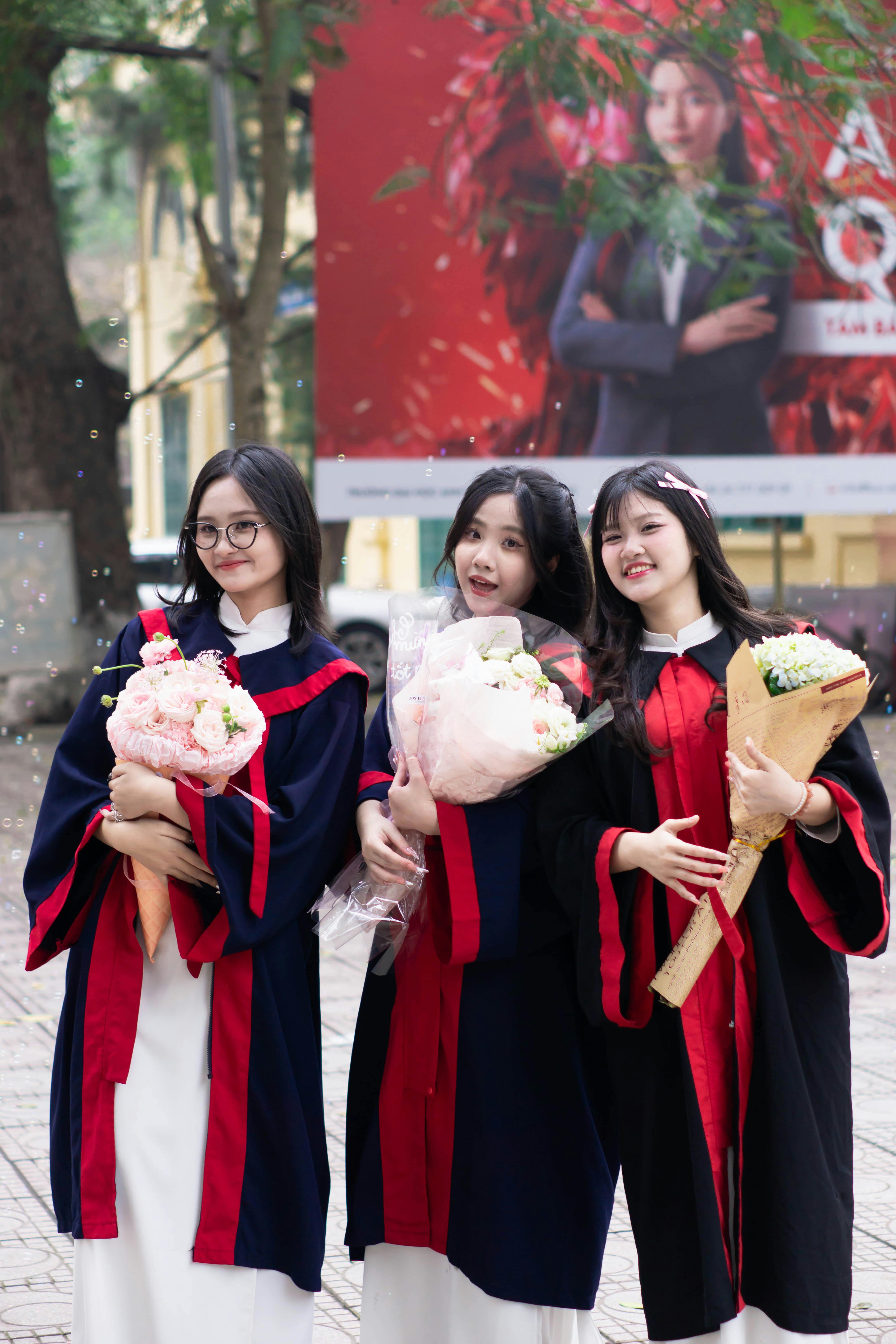 Joyful Graduation Celebration with Bouquets Outdoors · Free Stock Photo