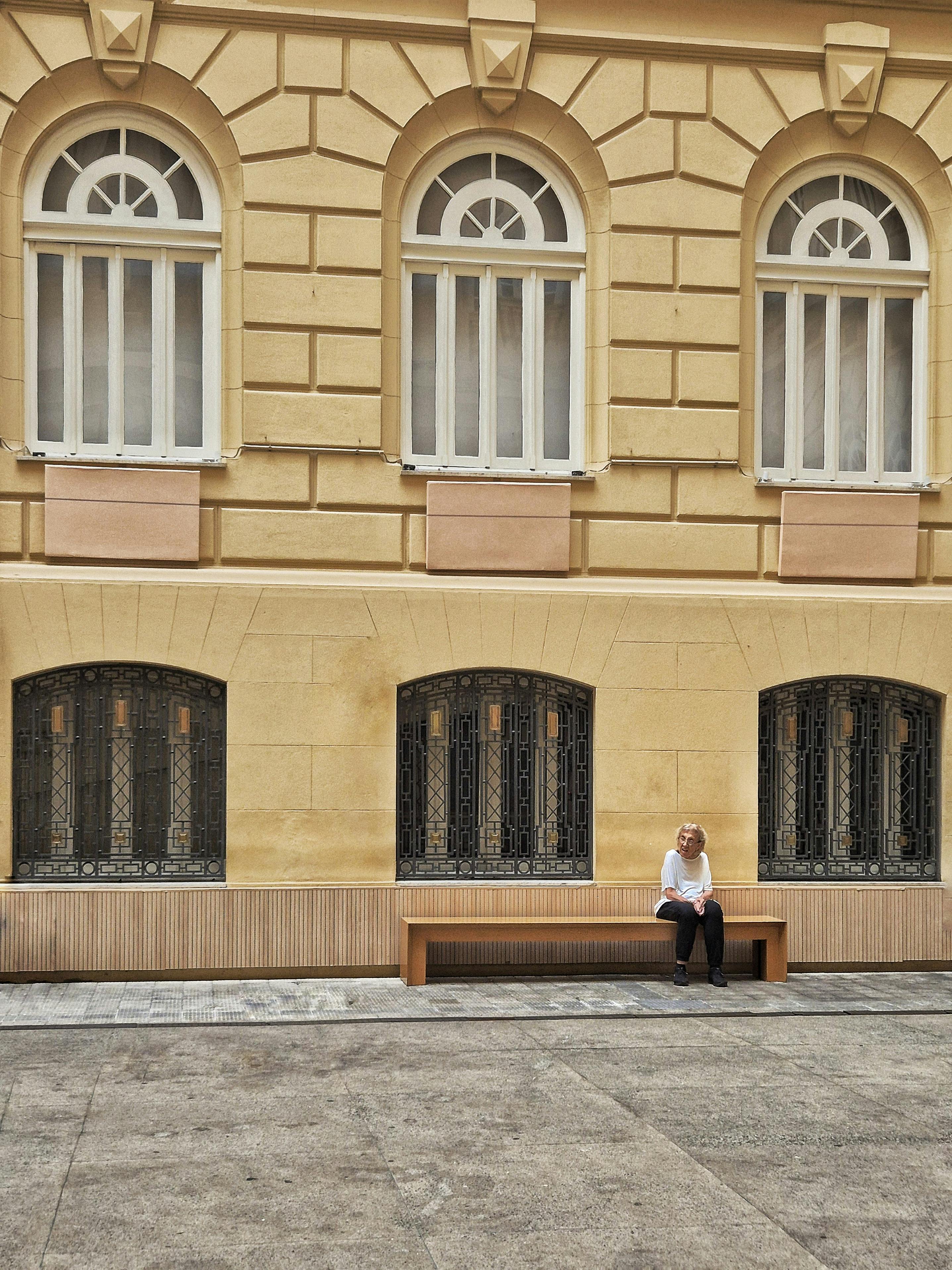 Woman Sitting on Bench by Historic Building · Free Stock Photo