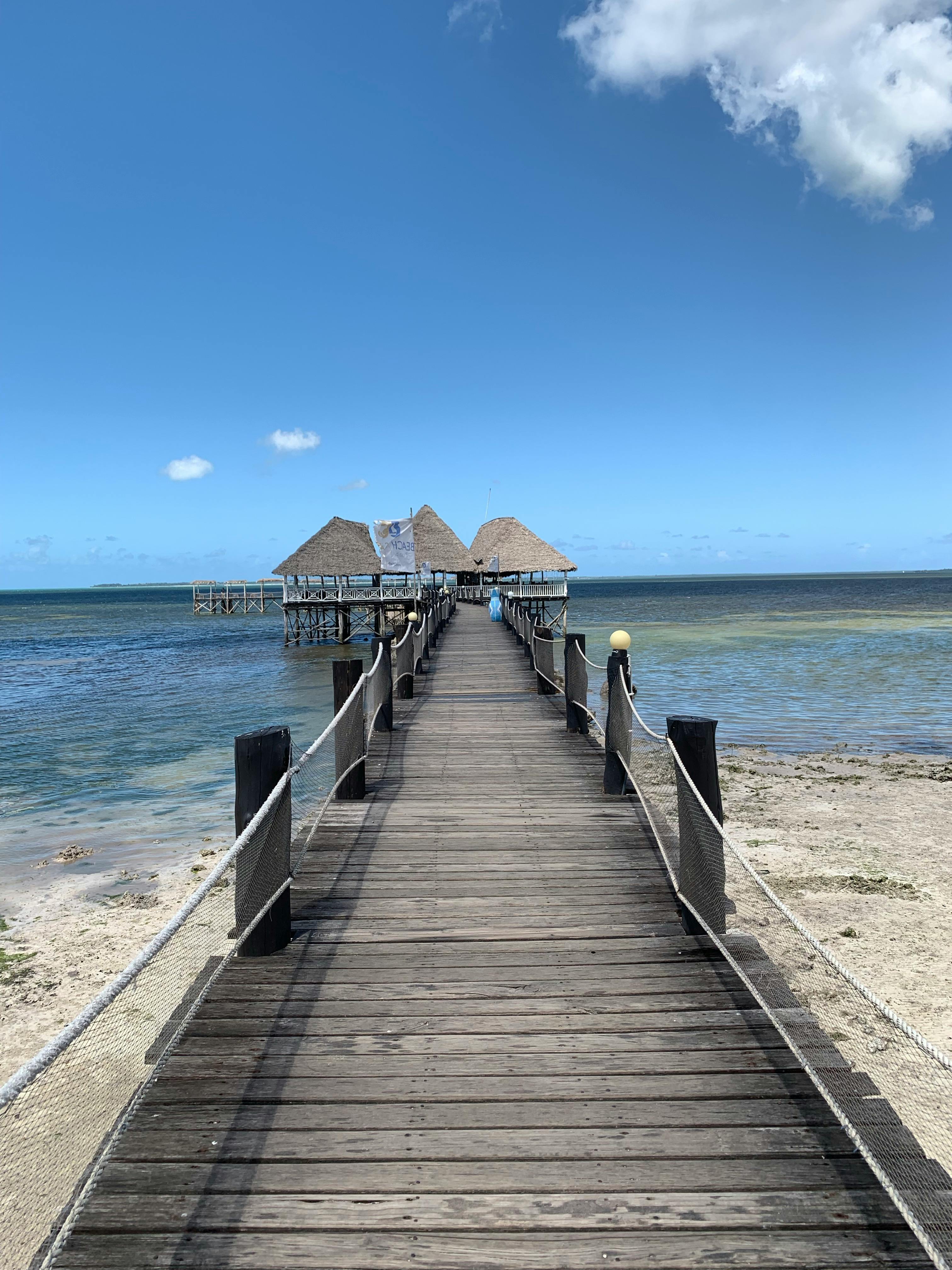 Scenic Pier Leading to Beachfront Huts · Free Stock Photo