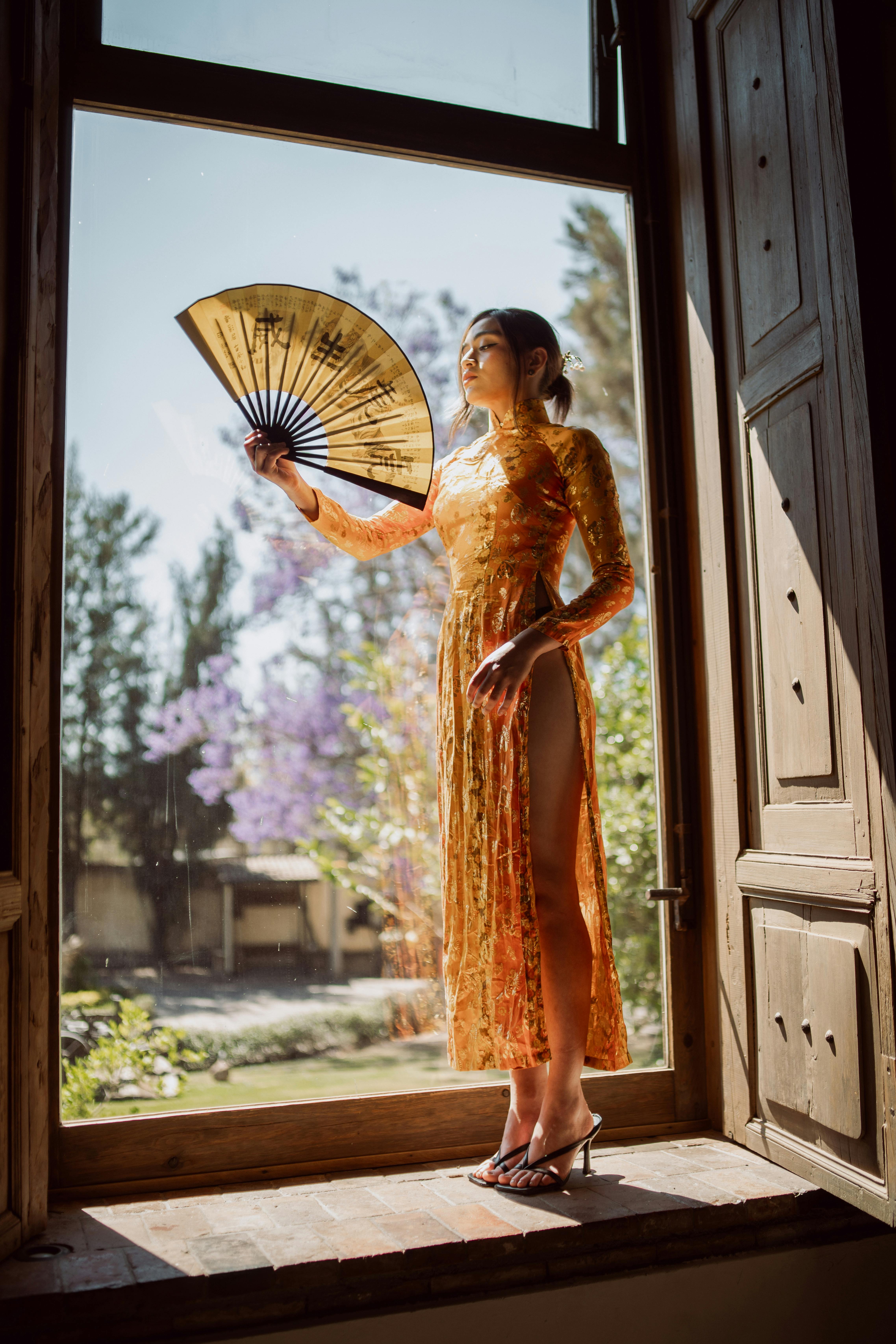 Elegant Woman in Yellow Dress Holding Decorative Fan · Free Stock Photo
