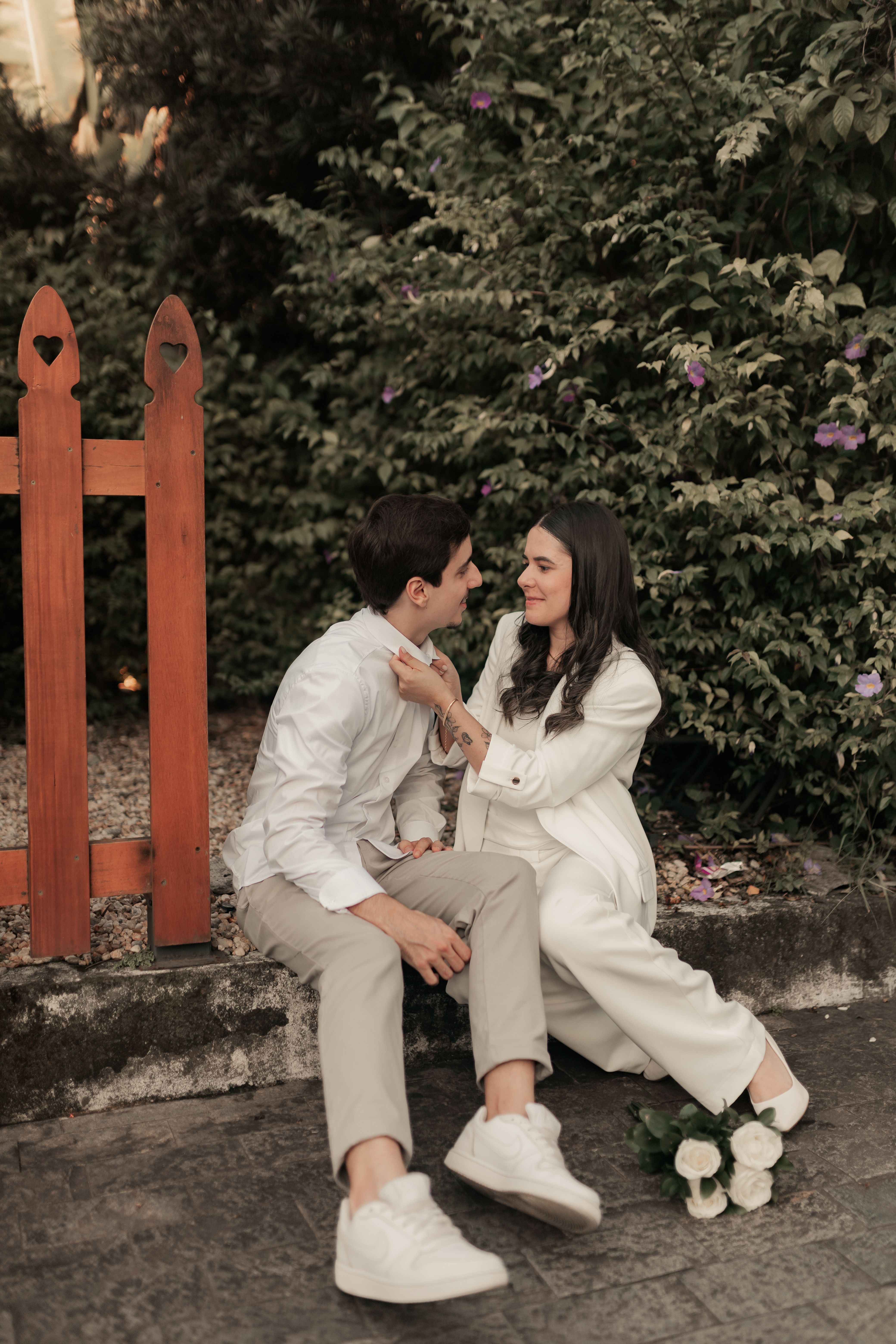 Romantic Couple Sitting by Red Fence Outdoors · Free Stock Photo