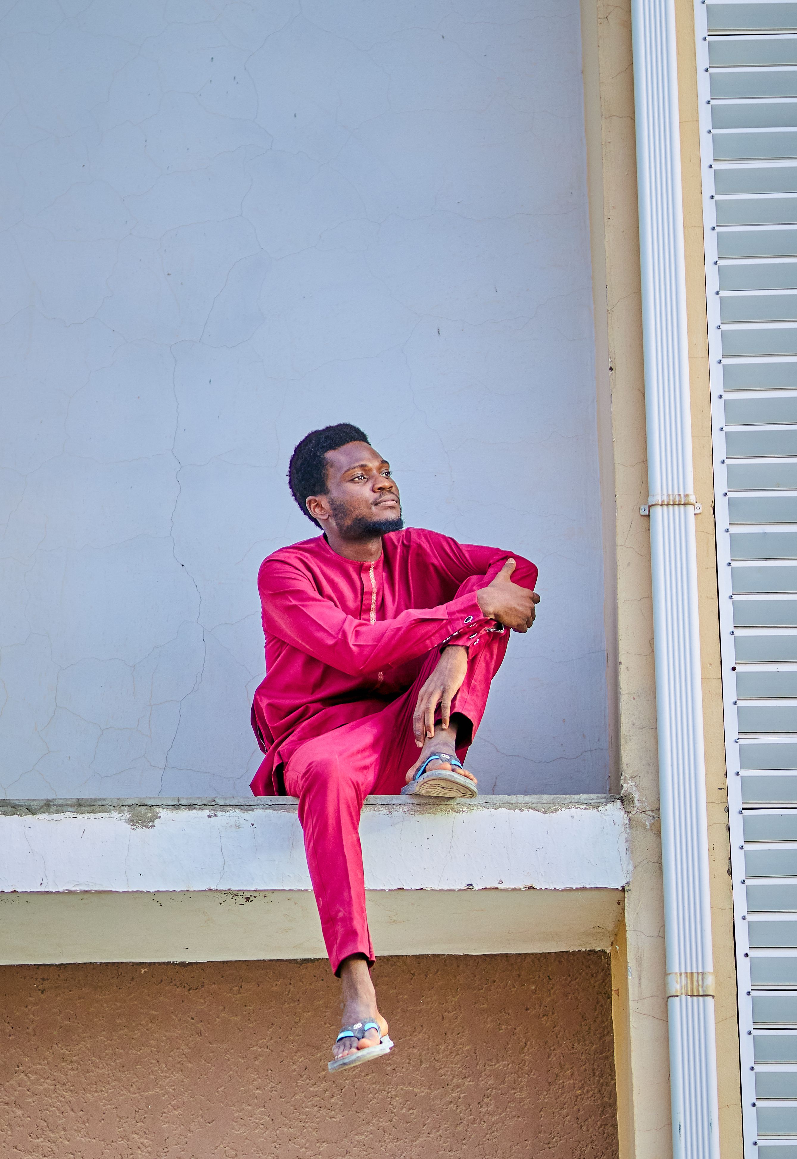 Man in Red Traditional Clothing Sitting Outdoors · Free Stock Photo