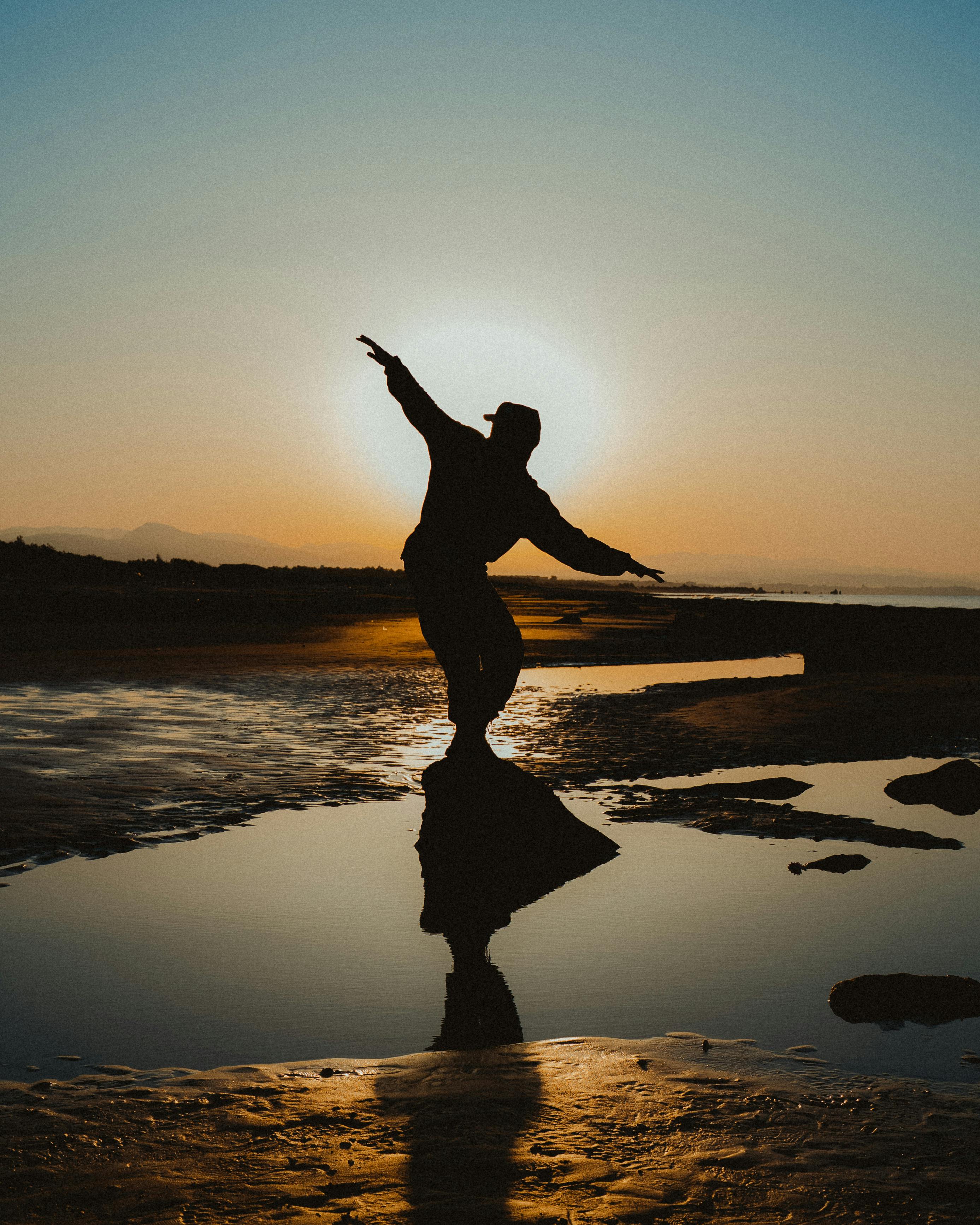 Silhouette of a Person Balancing on Beach Rocks at Sunset · Free Stock ...