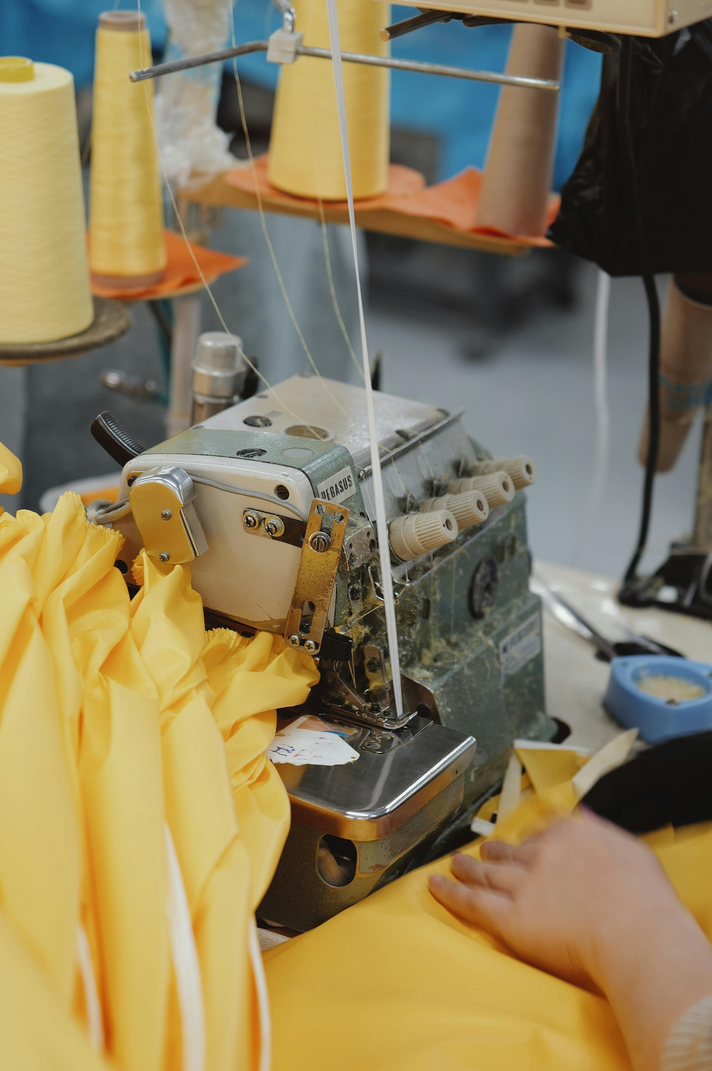 Hands operating sewing machine with yellow fabric · Free Stock Photo