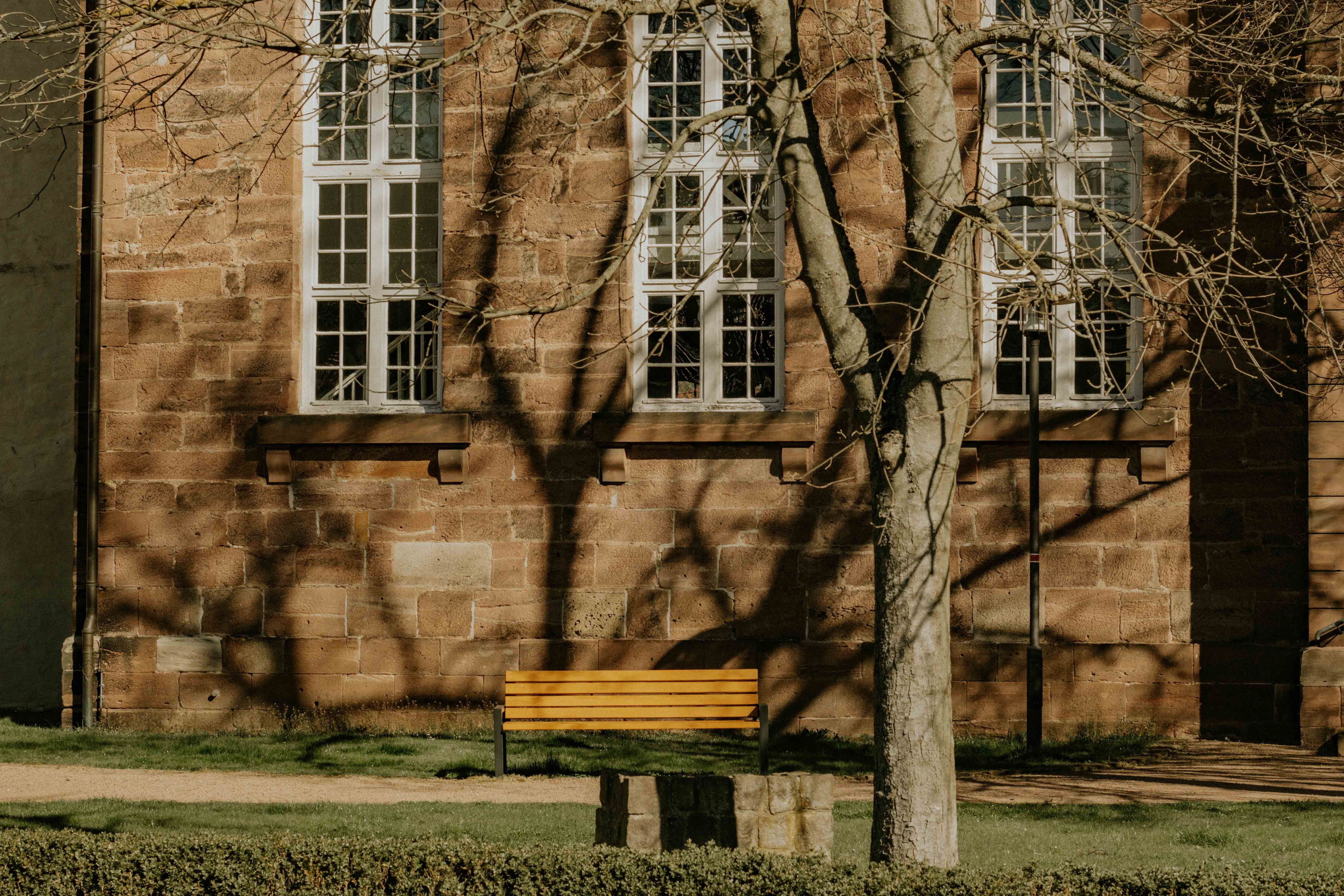 Sunlit Stone Building with Shadows and Bench · Free Stock Photo