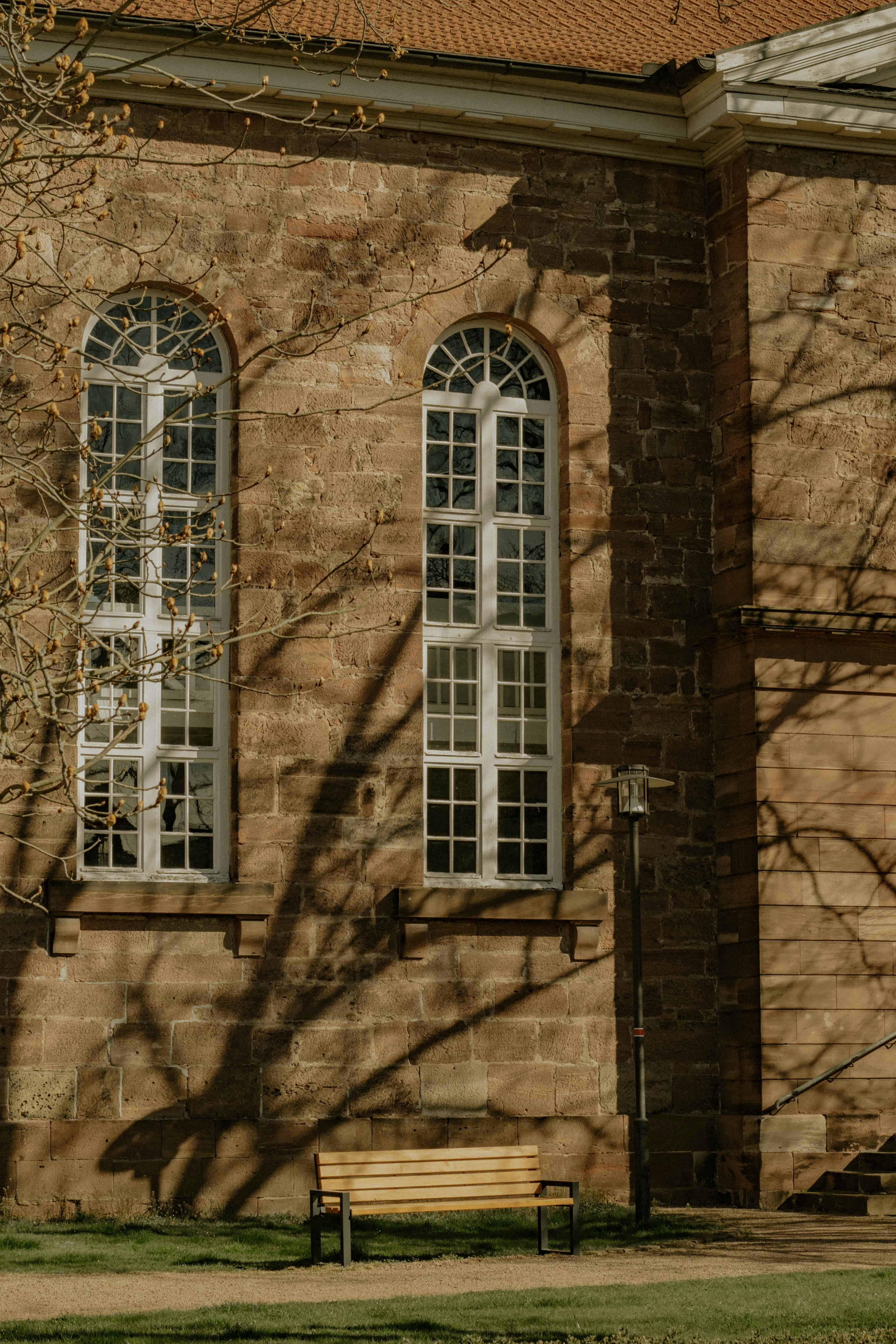 Sunlit Stone Building with Arched Windows and Shadows · Free Stock Photo