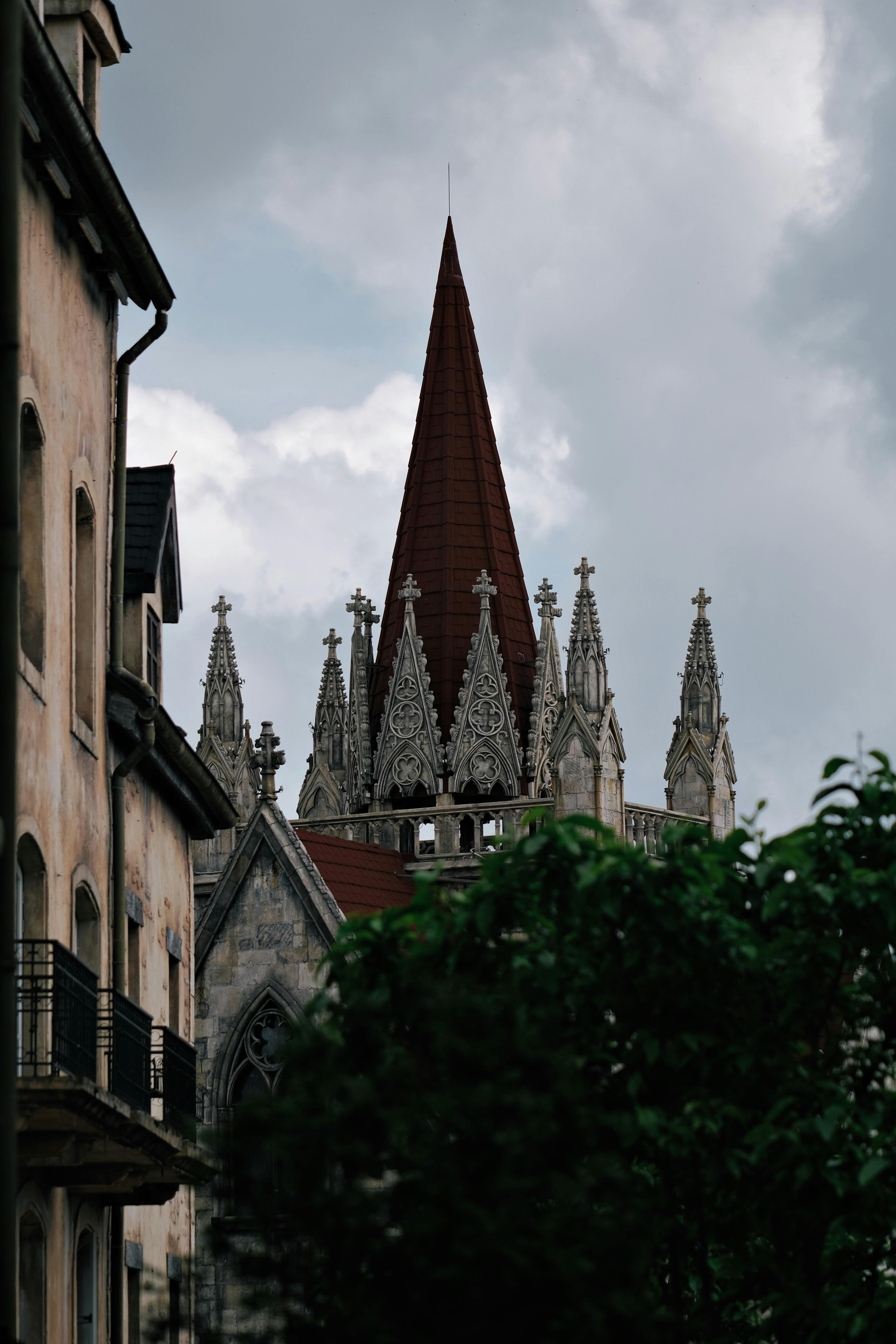 Gothic Cathedral Spire Against Cloudy Sky · Free Stock Photo