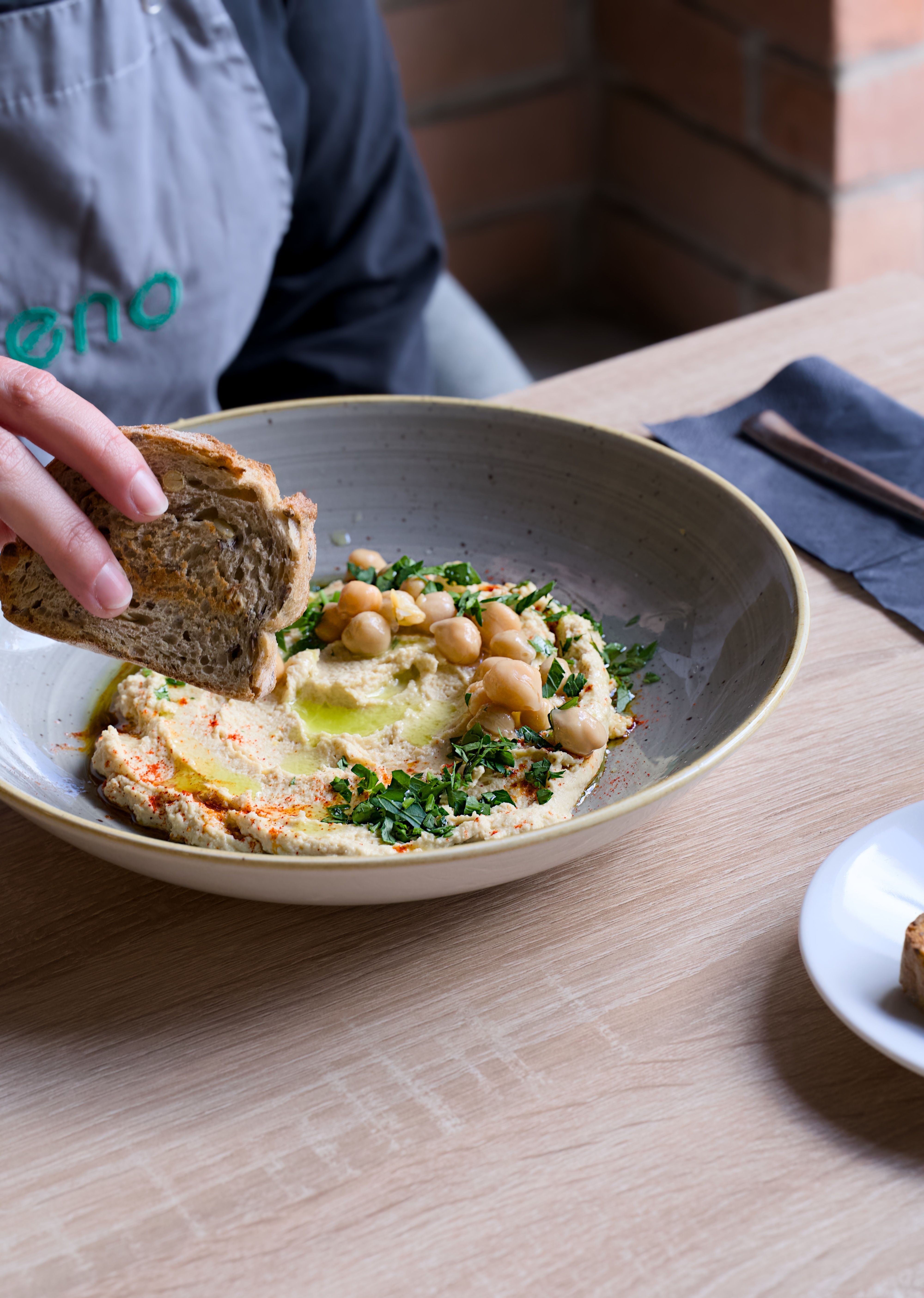 Person Enjoying Fresh Hummus with Bread at Cafe · Free Stock Photo