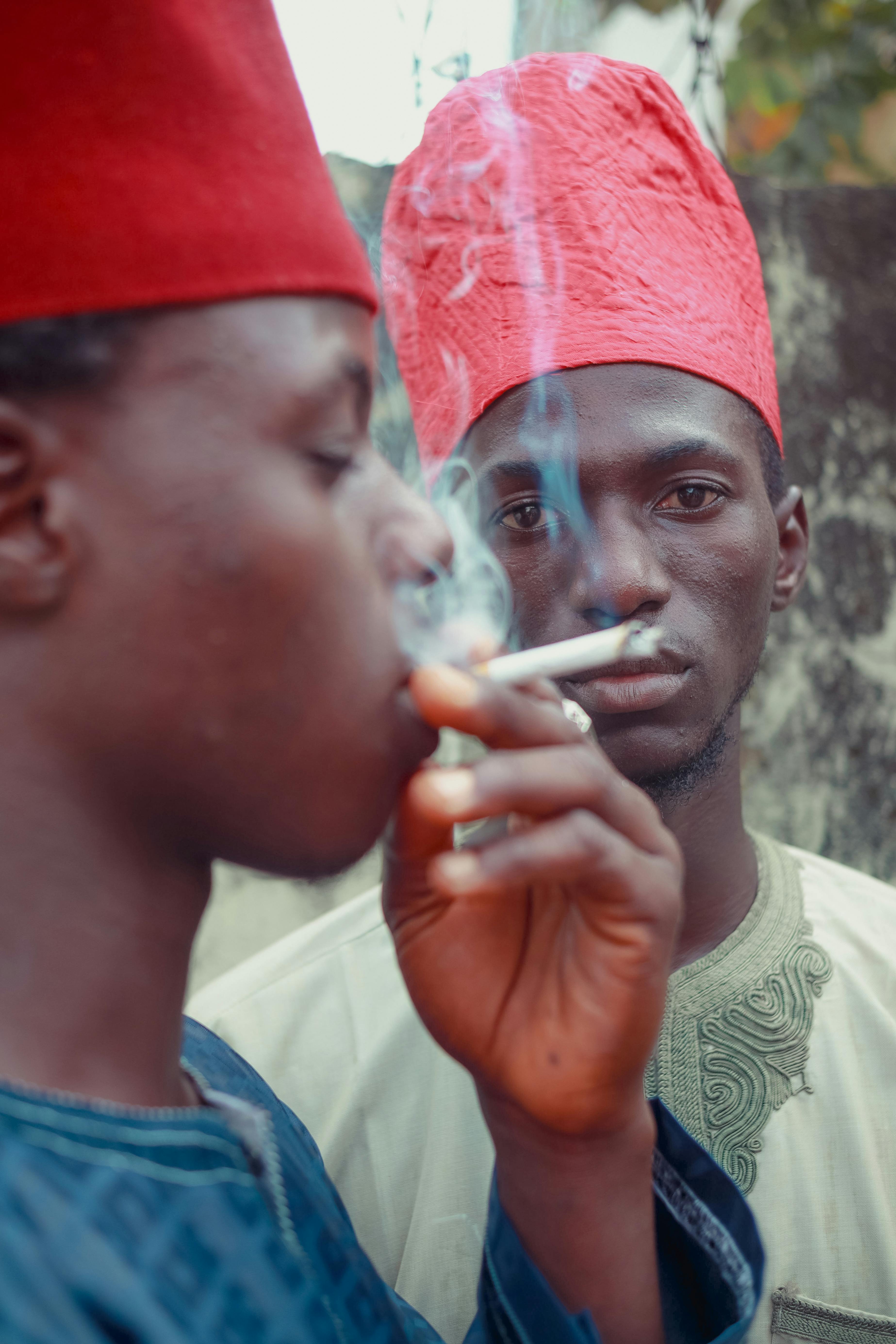 Two Men in Traditional Hats Smoking Cigarettes · Free Stock Photo