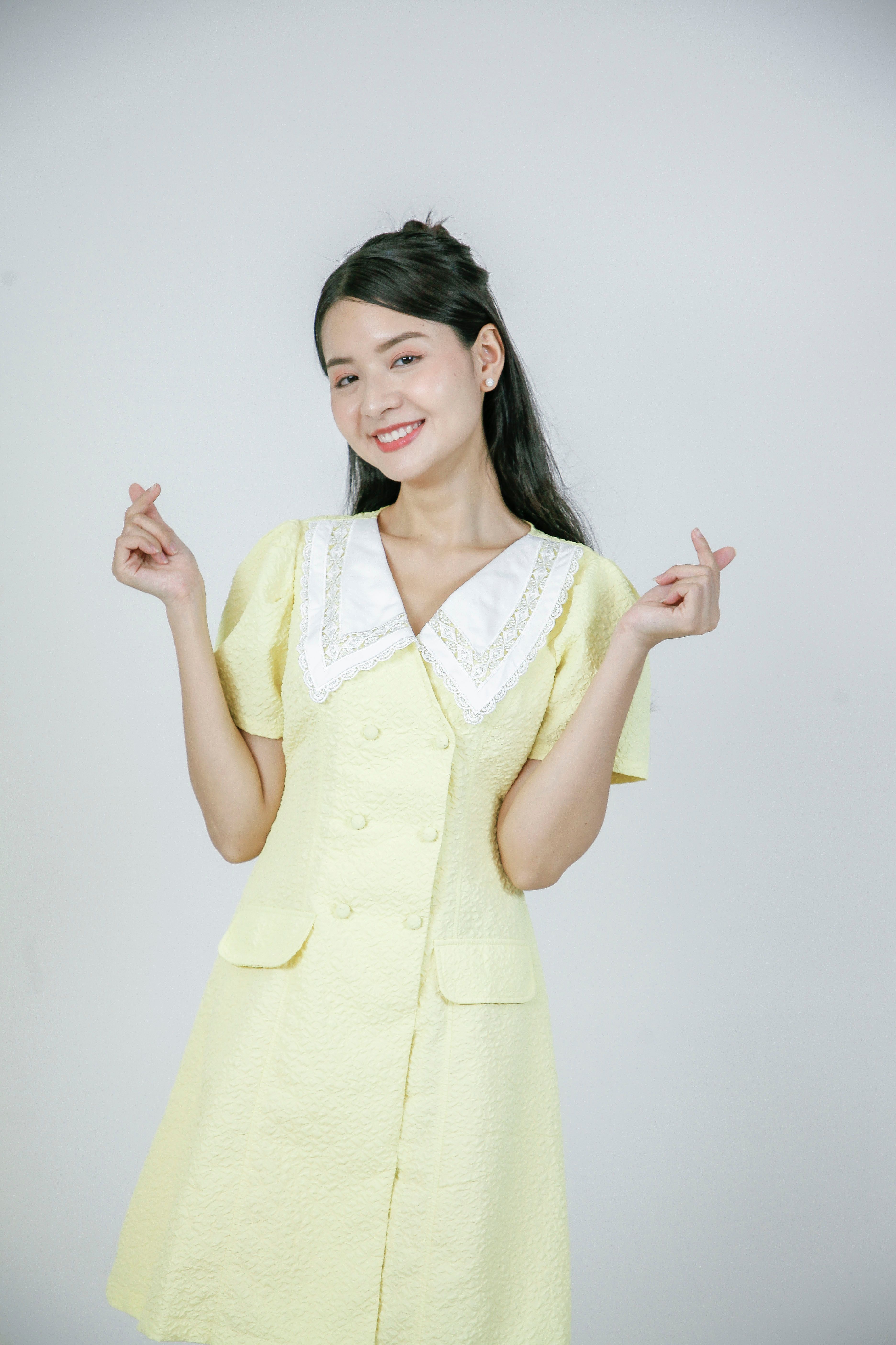 Smiling Woman in Yellow Dress Making Finger Hearts · Free Stock Photo