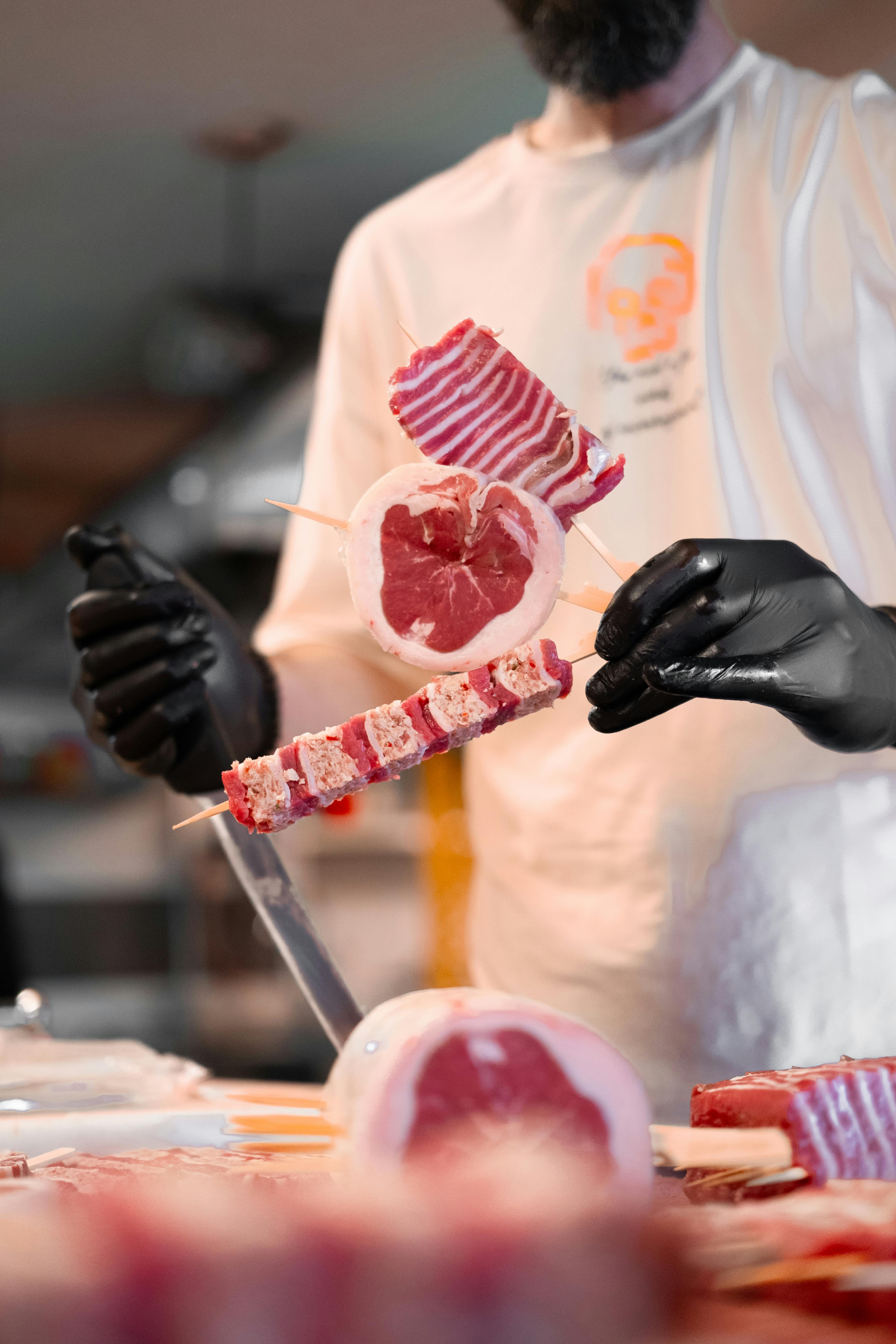 Butcher Preparing Skewered Red Meat Indoors · Free Stock Photo