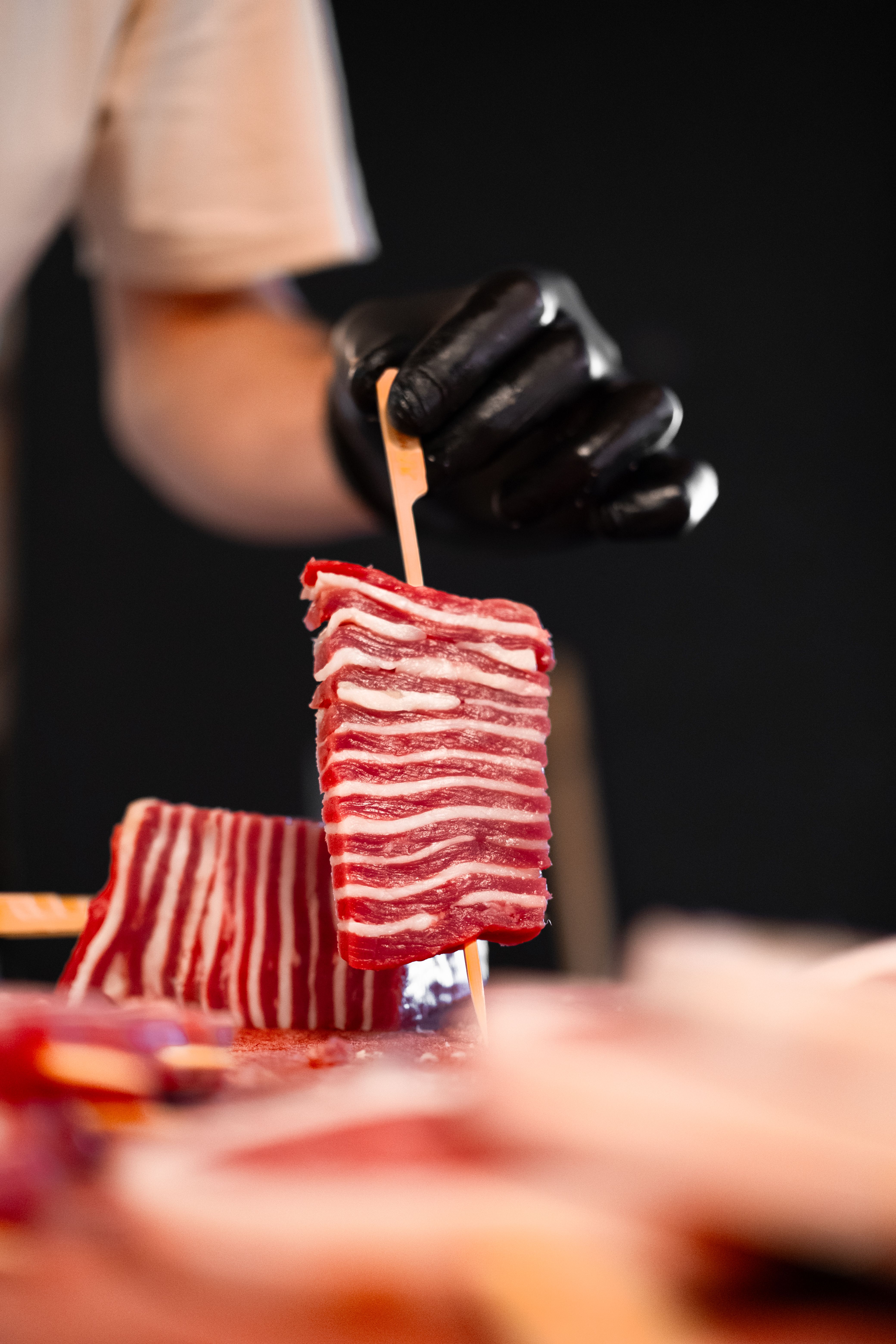 Gloved Hand Handling Skewered Red Meat · Free Stock Photo