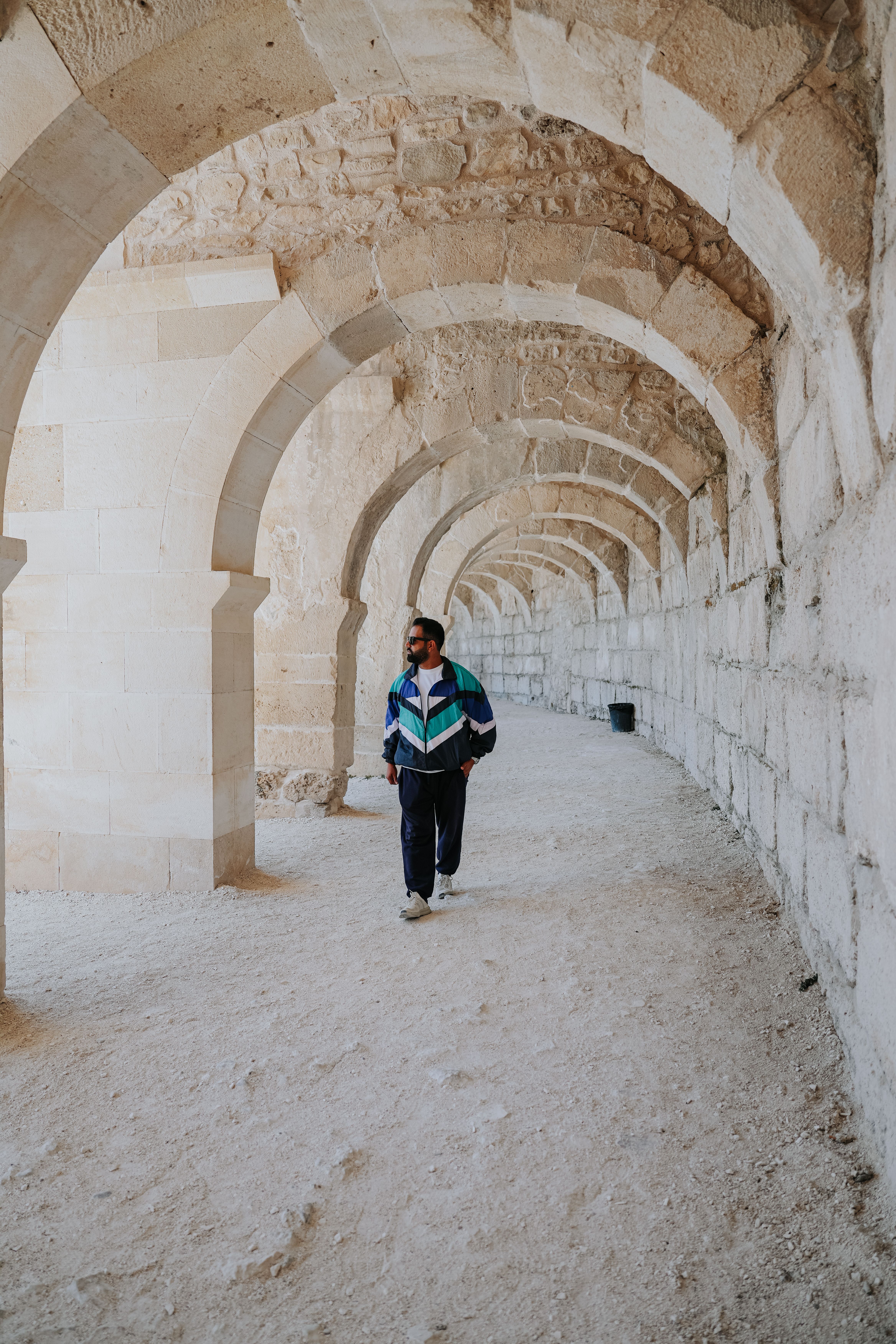 Man Walking Through Historical Stone Arches · Free Stock Photo