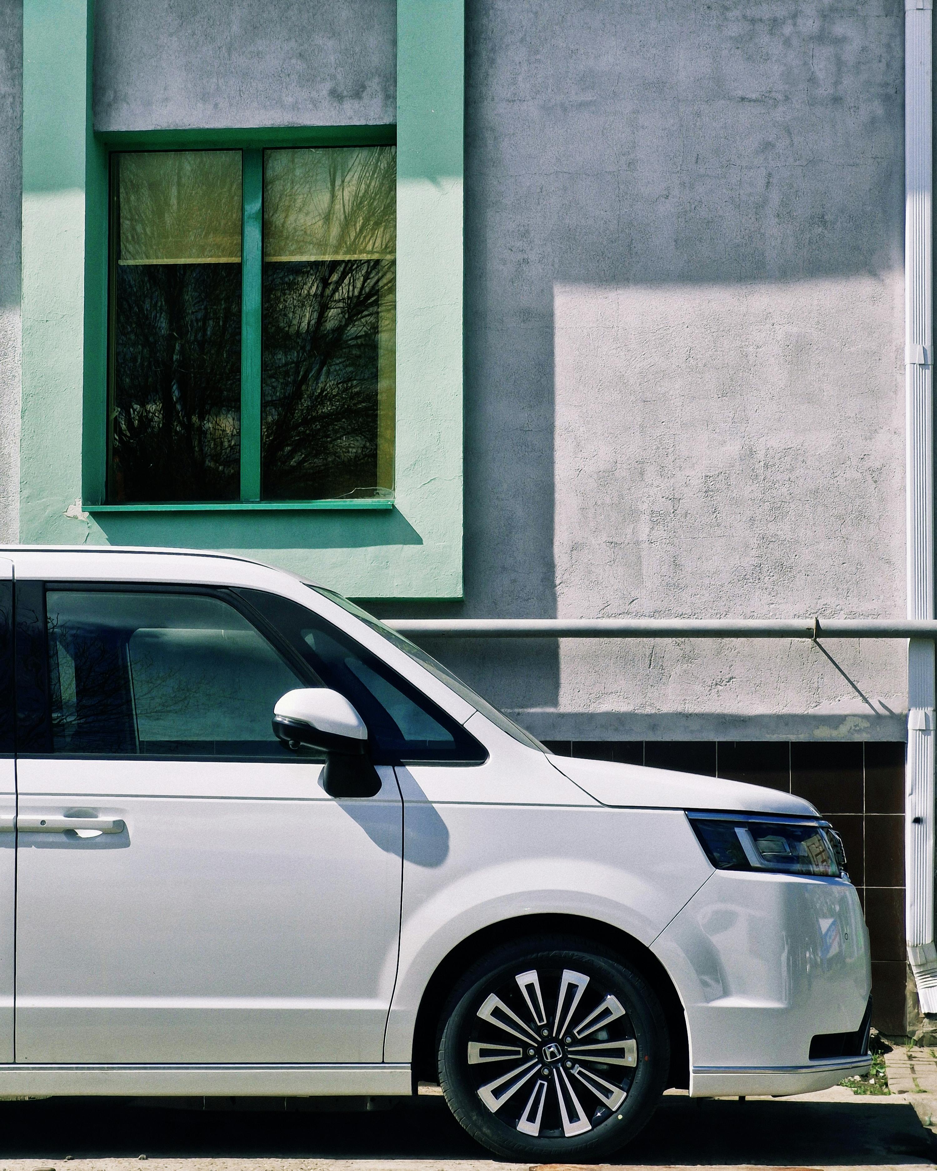 Modern White Minivan Parked Against Urban Wall · Free Stock Photo