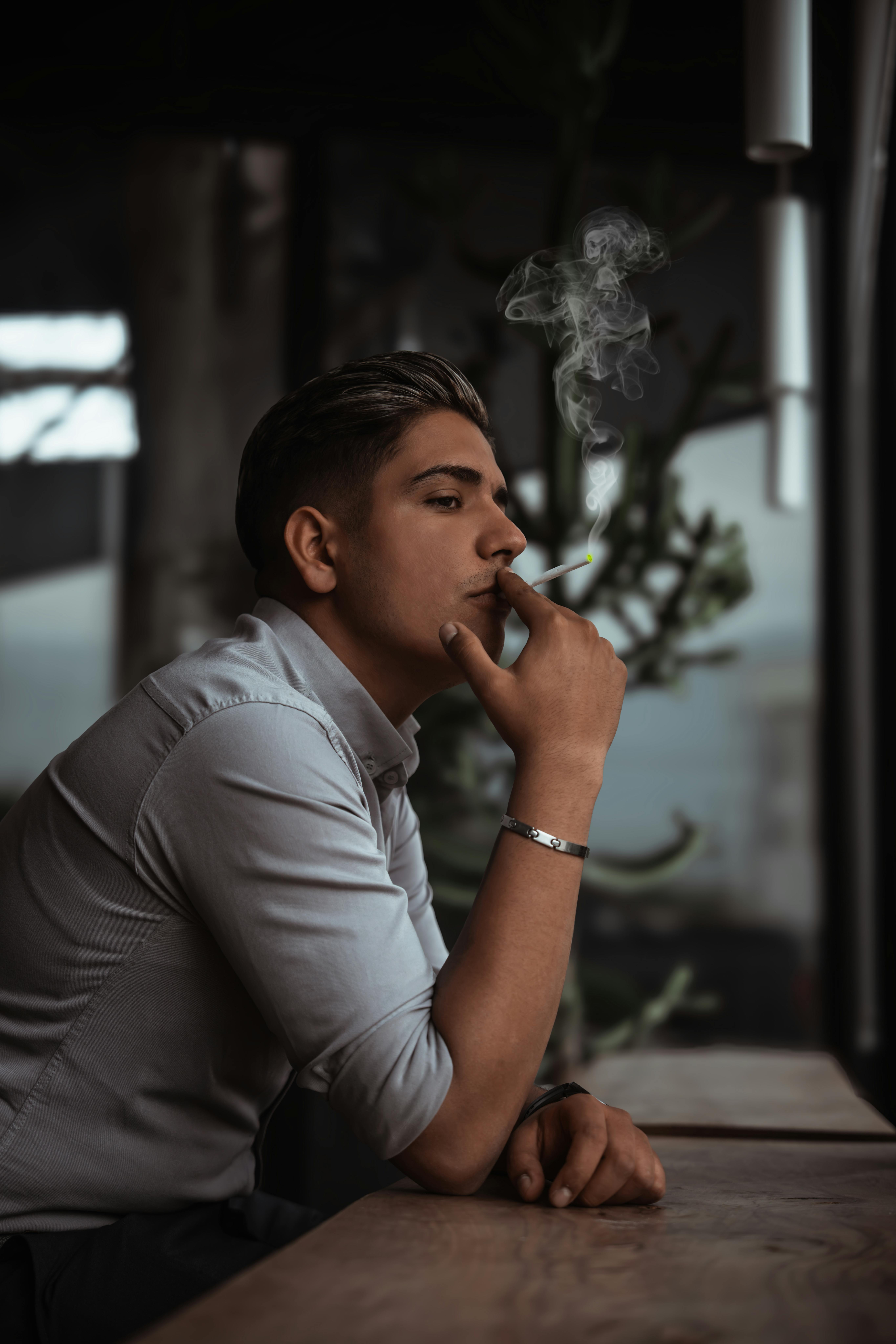 Pensive Man Smoking Indoors by Window · Free Stock Photo